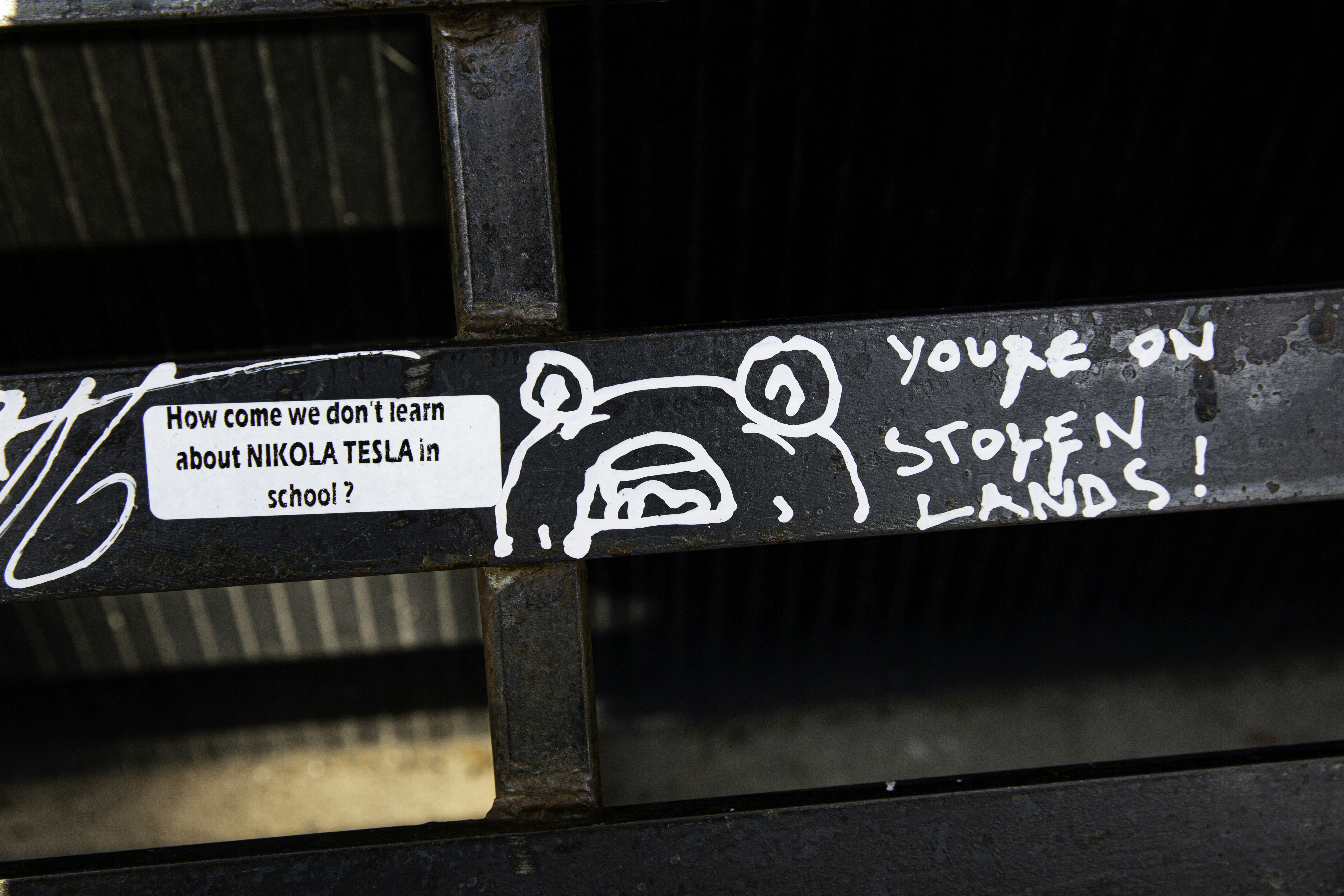 Graffiti on a Weathered Metal Railing: A Message in White Ink