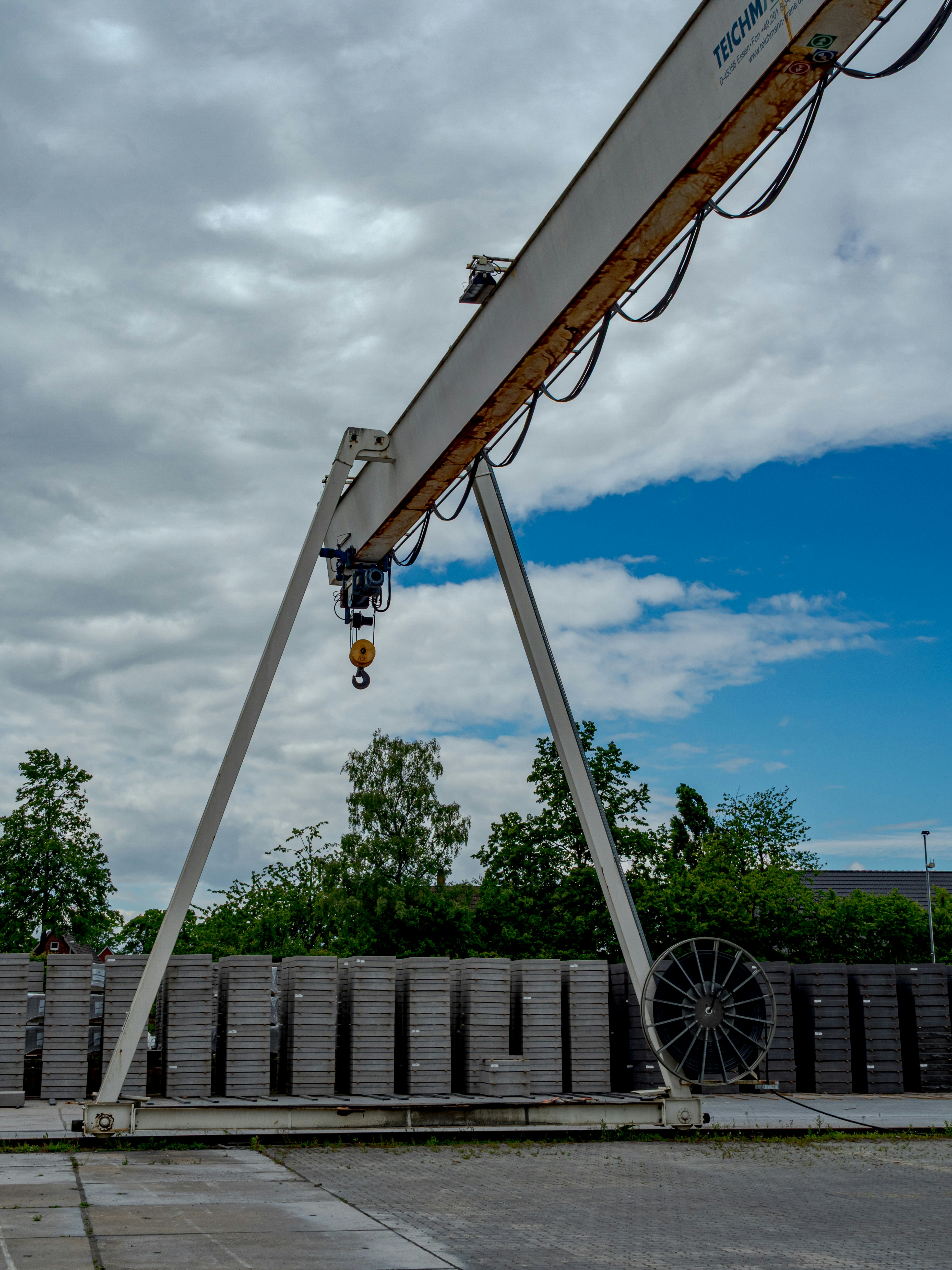 Industrial Crane Arc: A Crane Arm Reaching Over a Row of Concrete Barriers
