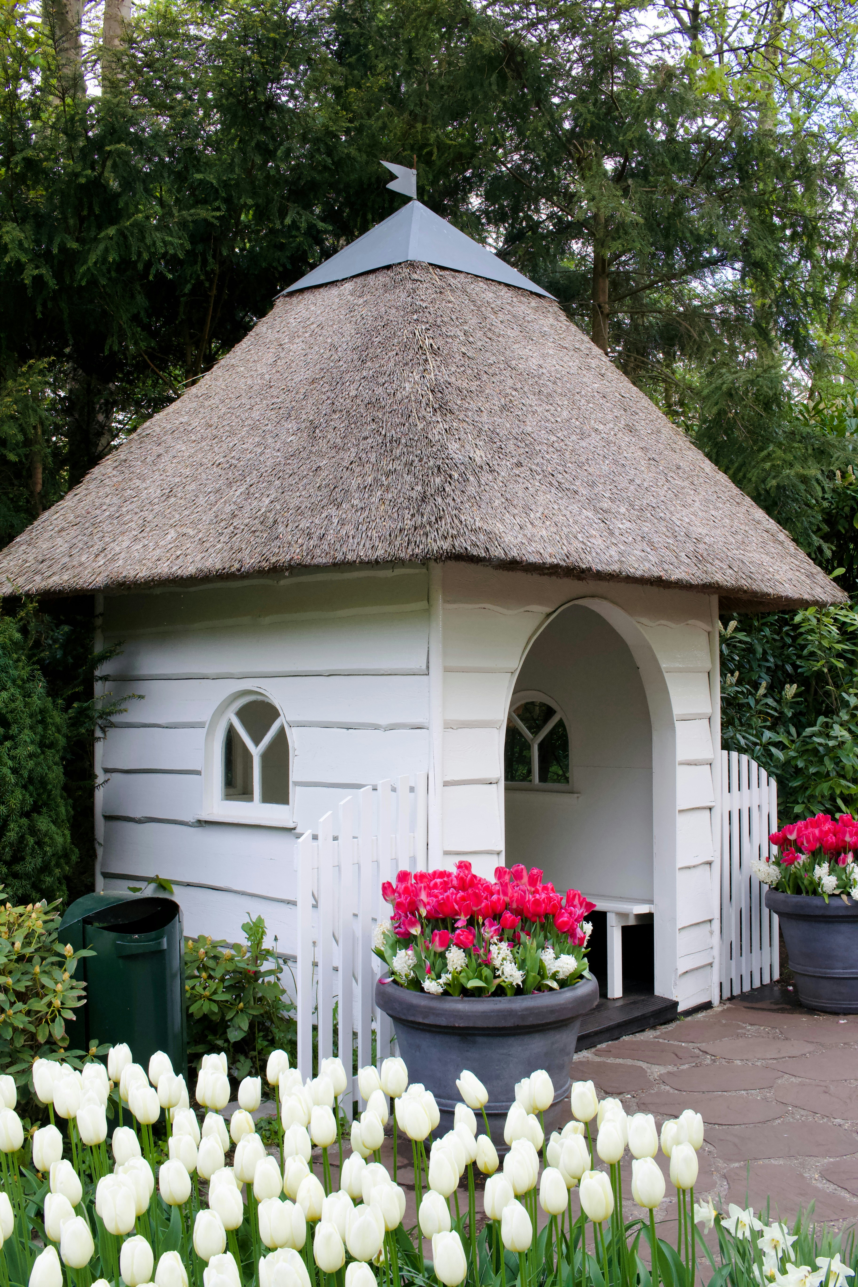 White cottage with thatched roof tucked among spring blooms