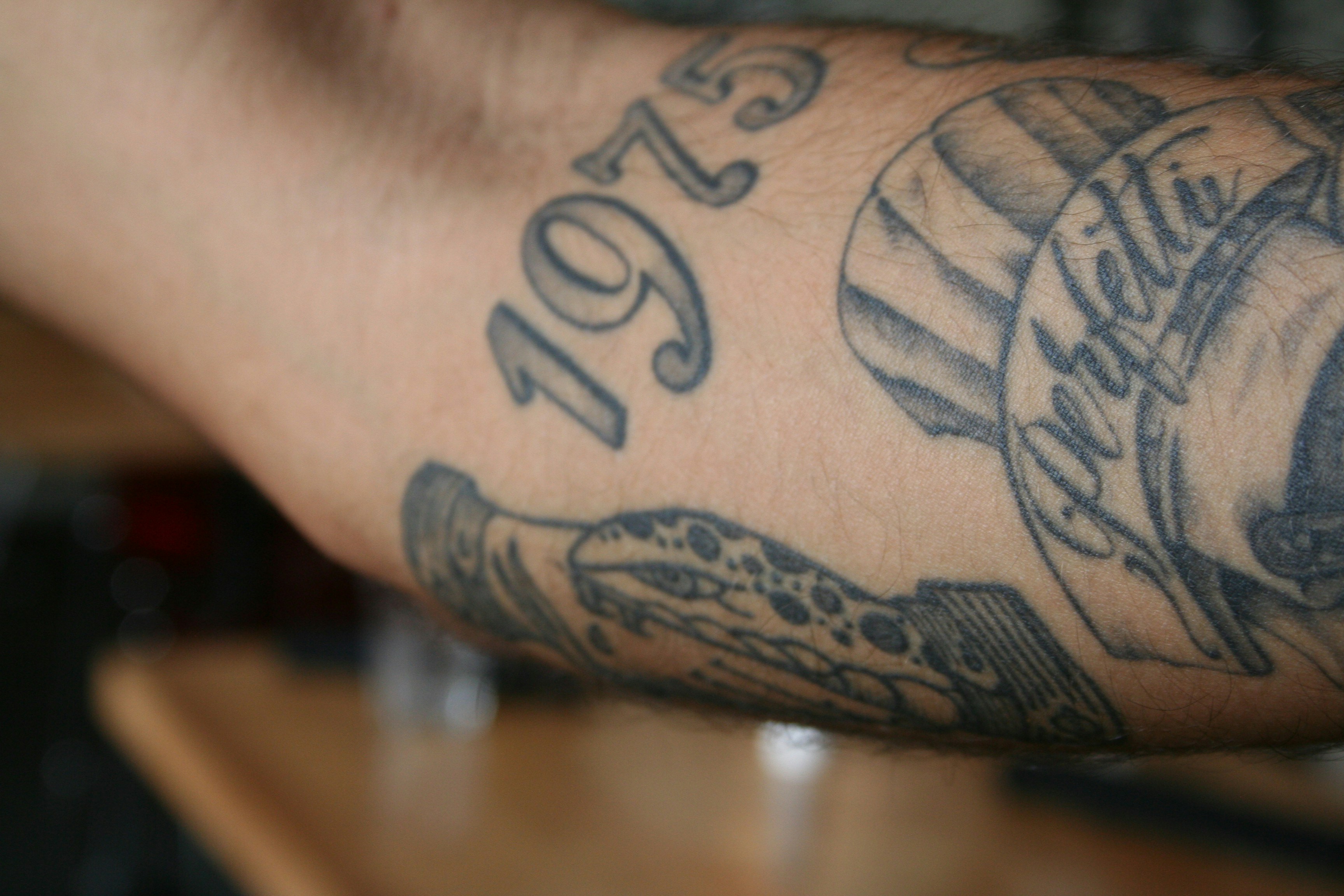 Ink and skin: a tattooed forearm resting on a wooden surface