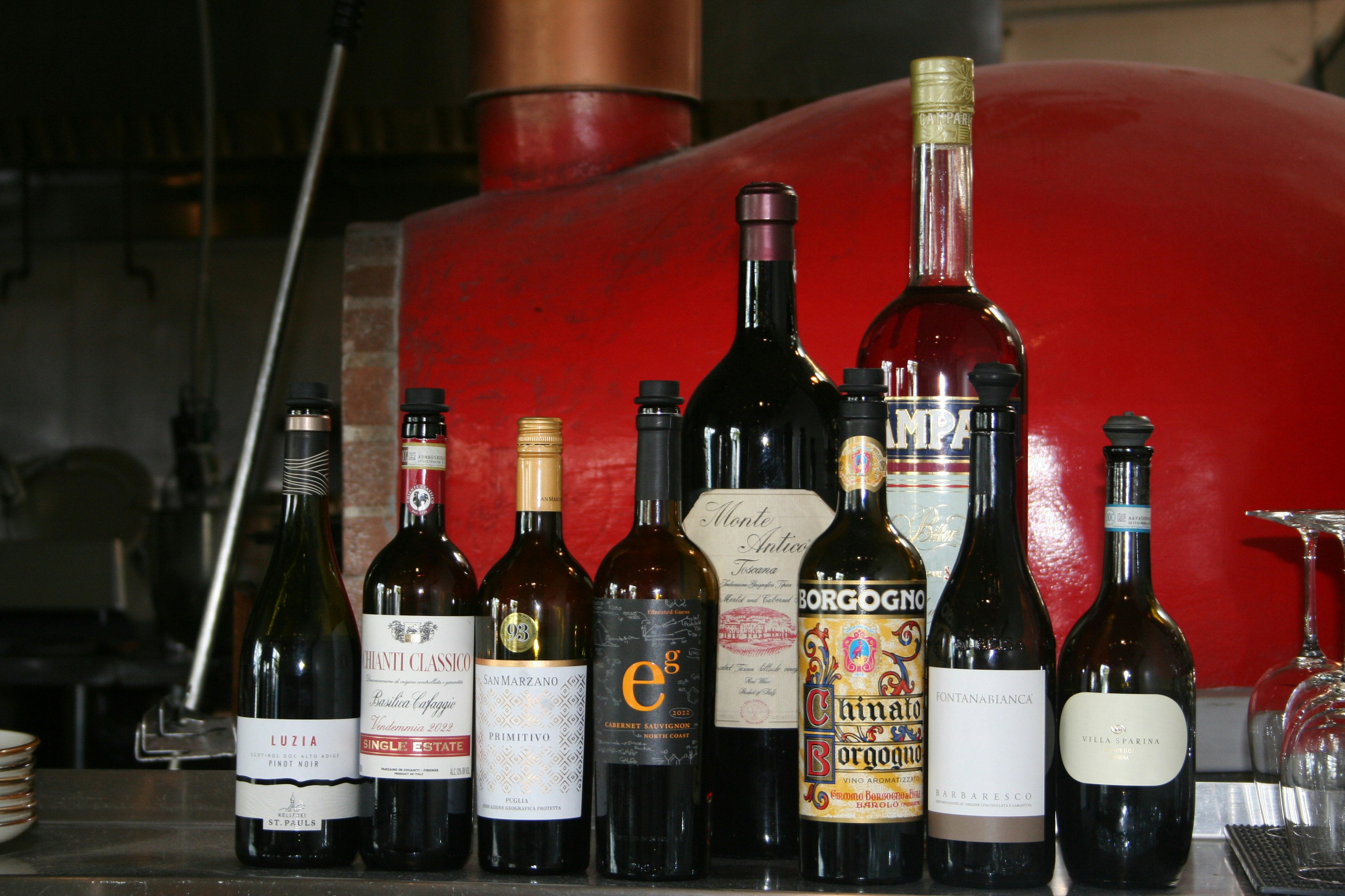 Row of Wine Bottles on a Bar Against a Red Boiler Cloud