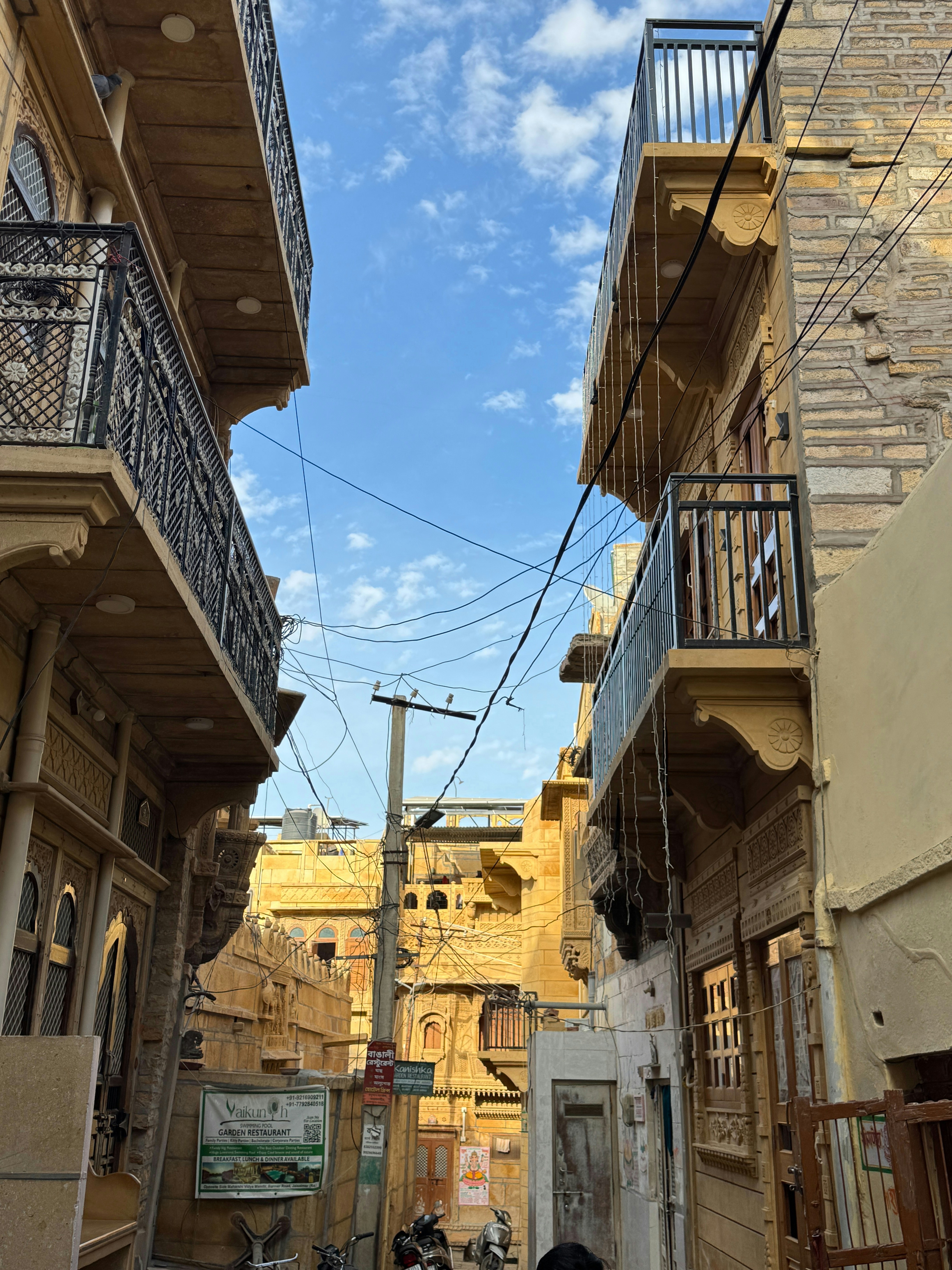 Skinny Alleyway Between Ornate Balconies Under a Bright Blue Sky