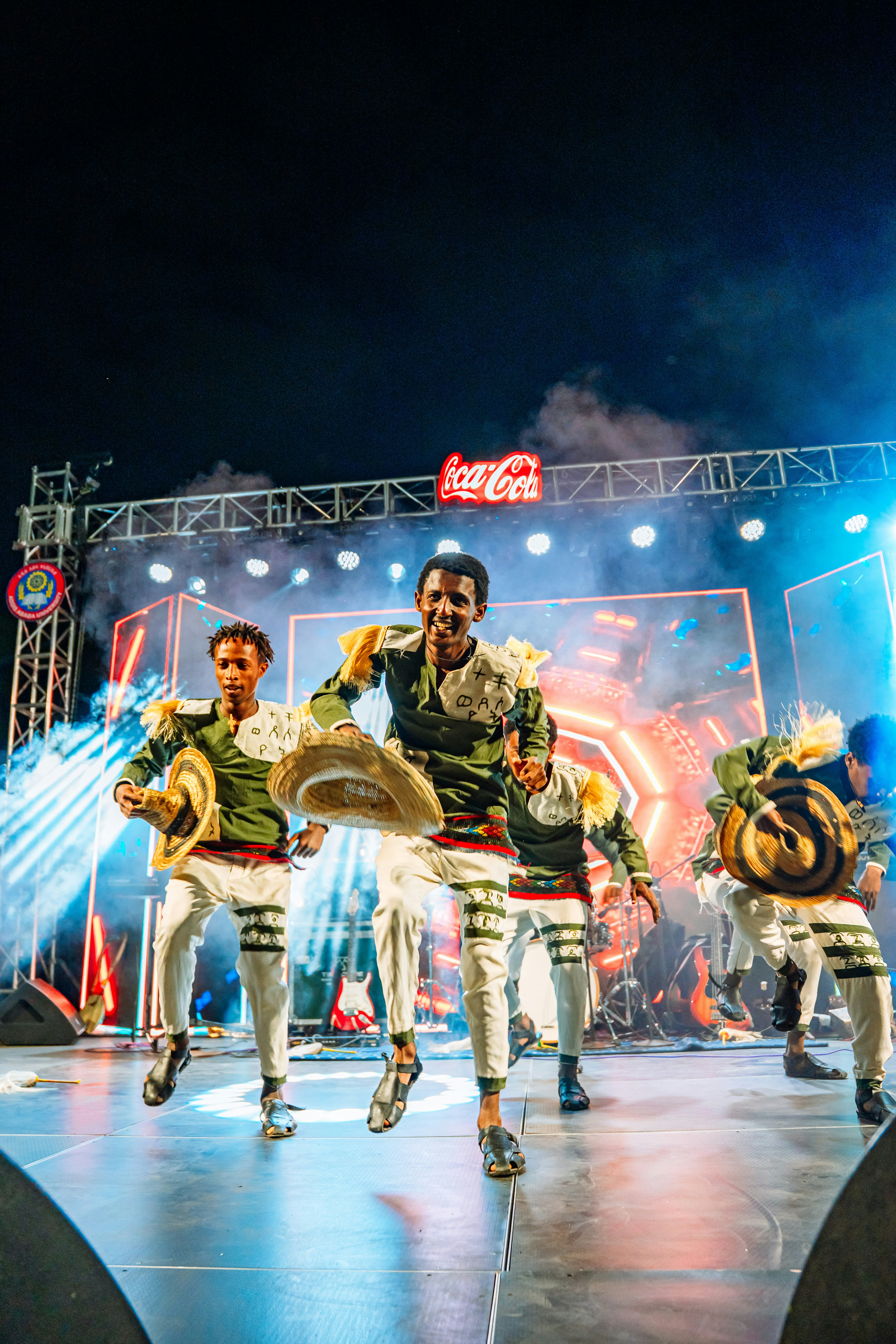 Energetic Zap in Neon Rings: Dancers Leap Under Stage Lights