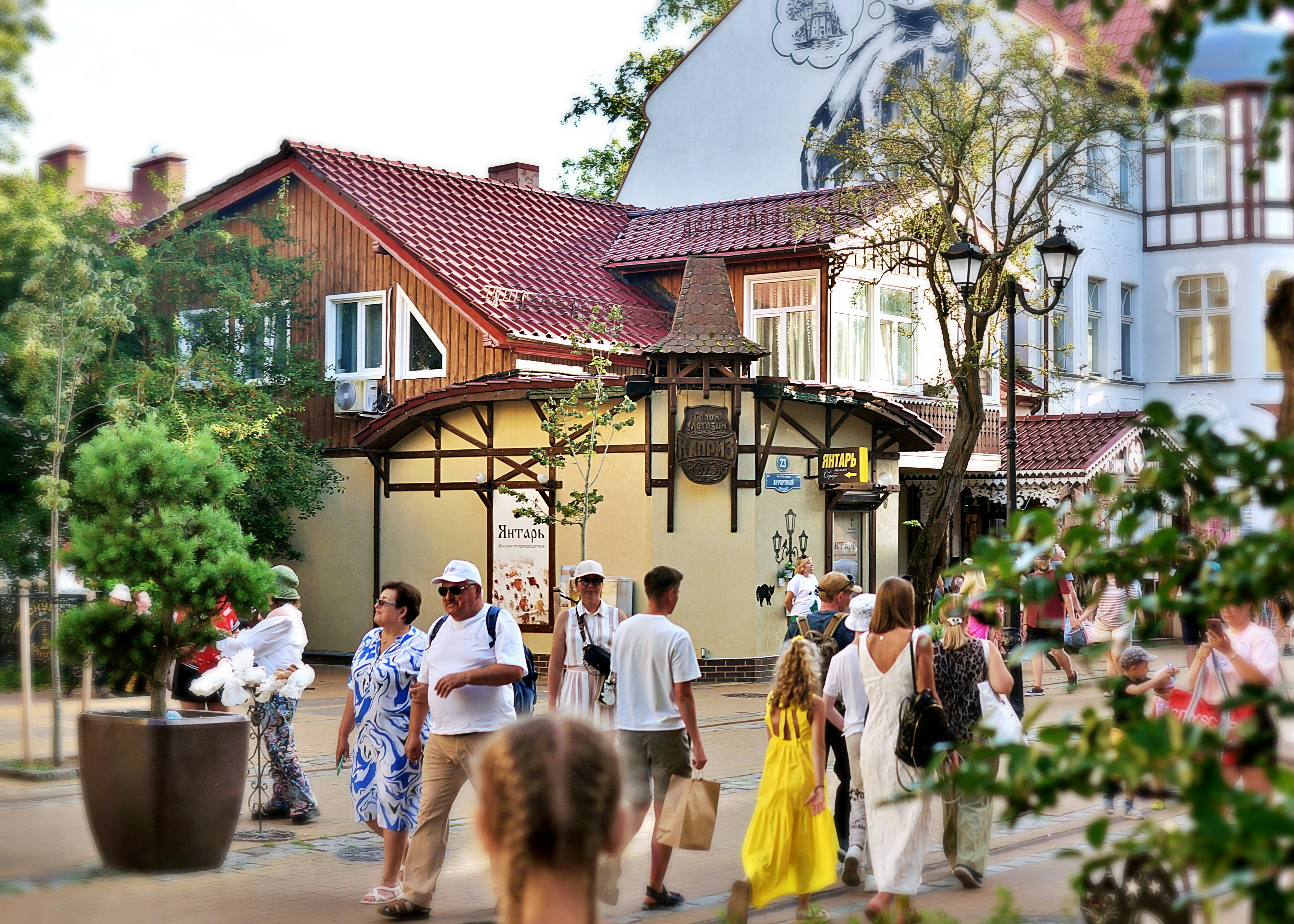 Village Square in Bloom: Tourists Gather Under a White-Facade Market