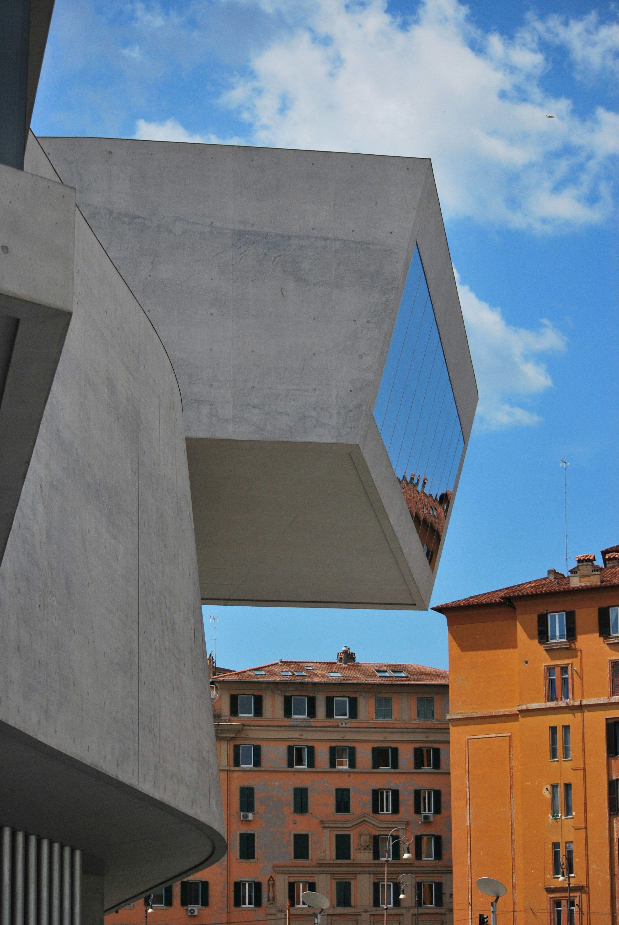 Concrete cantilever against blue sky with orange courtyard buildings