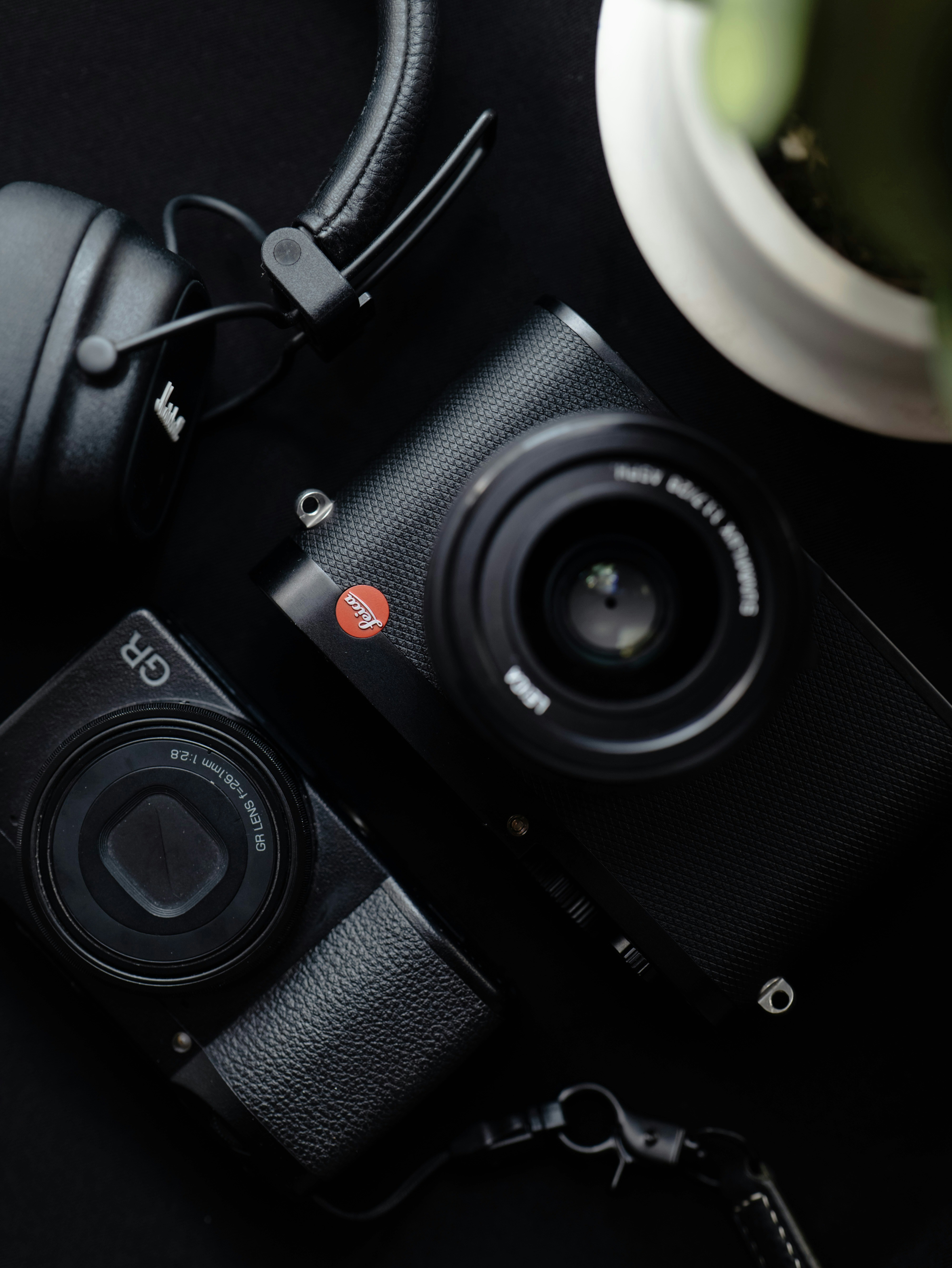 Two black cameras and headphones on a dark surface.