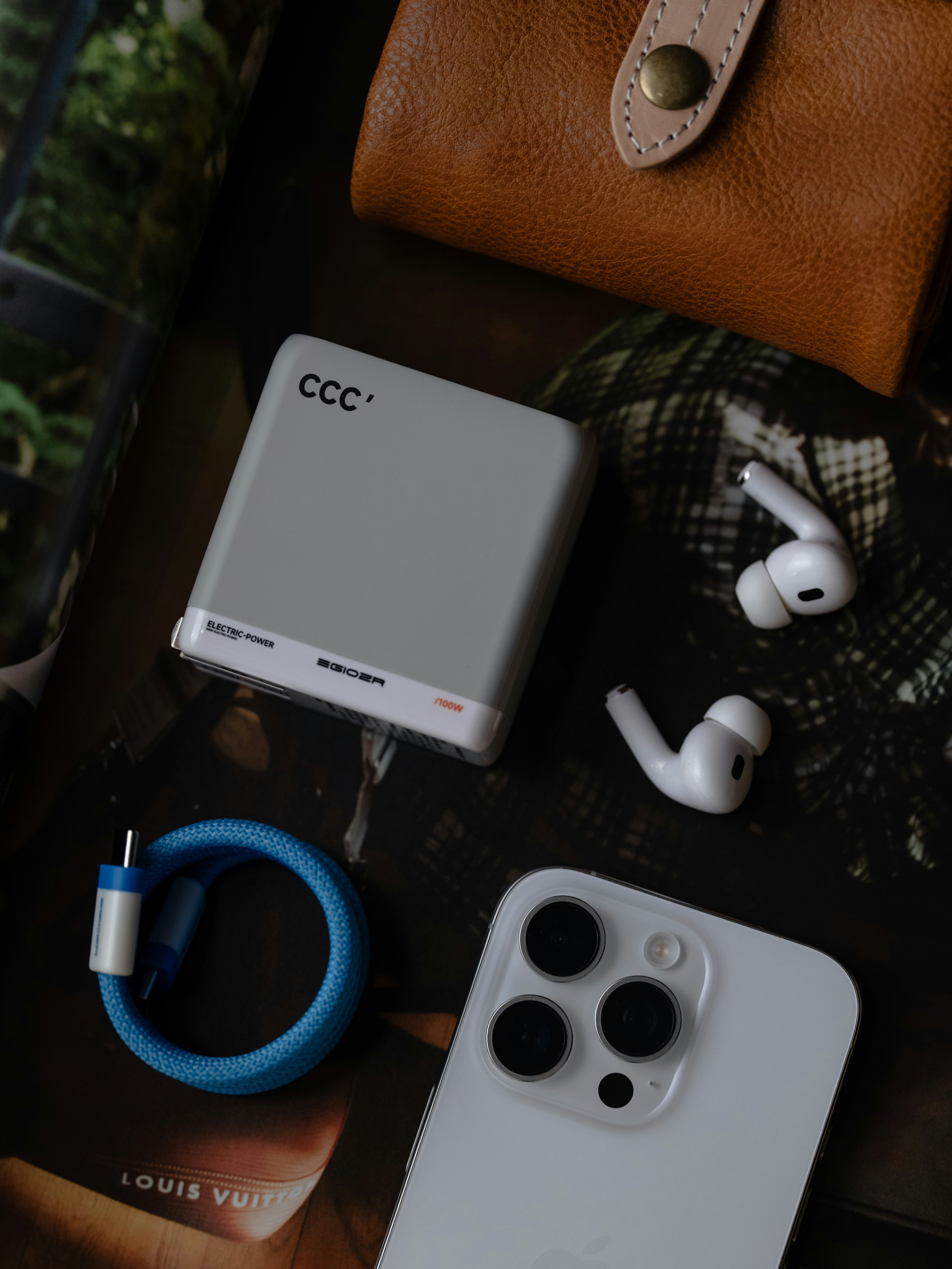 Tech Essentials on a Studio Slate: AirPods, USB-C Cable, and iPhone