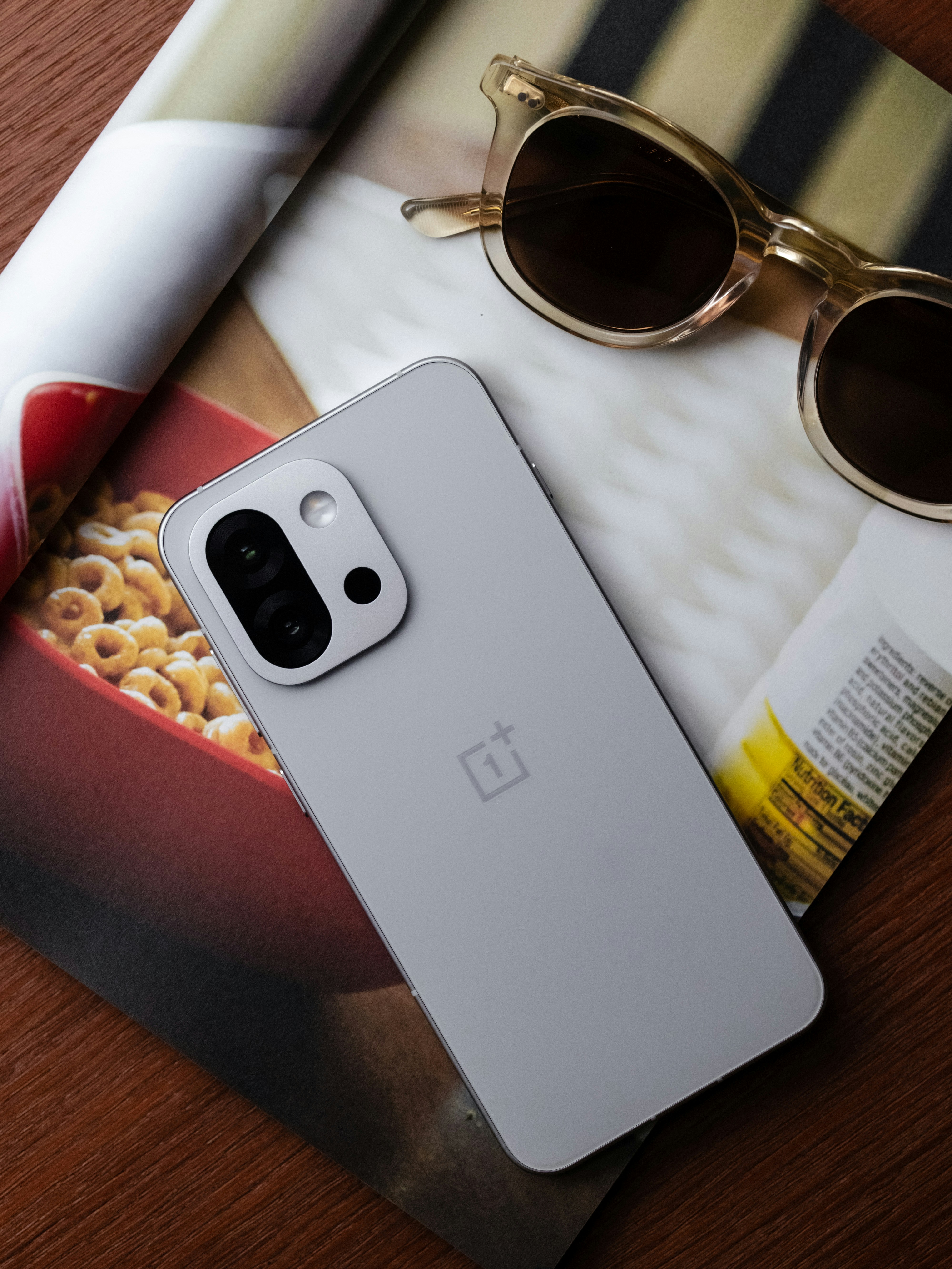 Minimal Tech Studio: White OnePlus Phone Resting on a Magazine