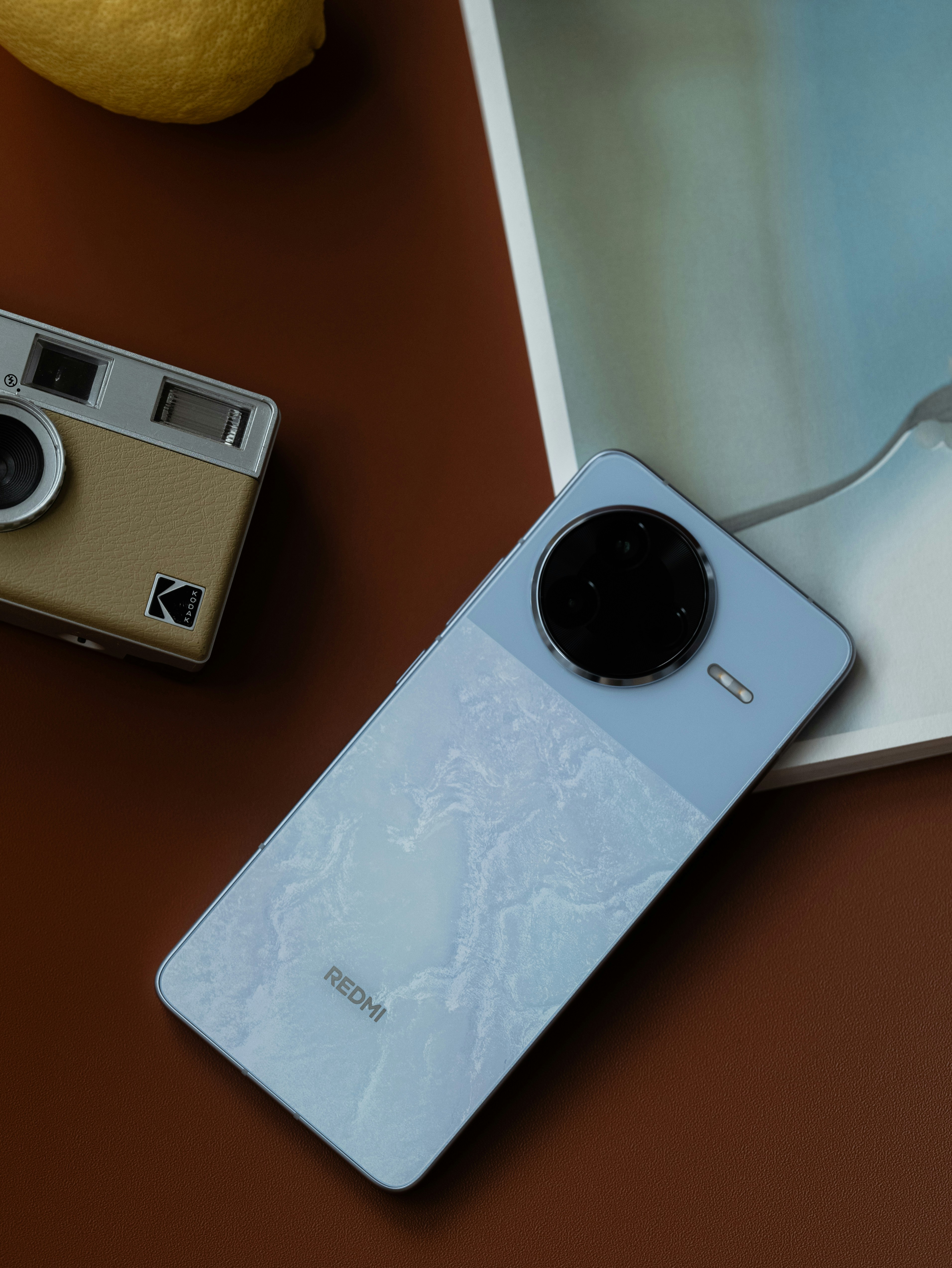 Ice Blue Redmi Phone Nestled Beside a Retro Camera