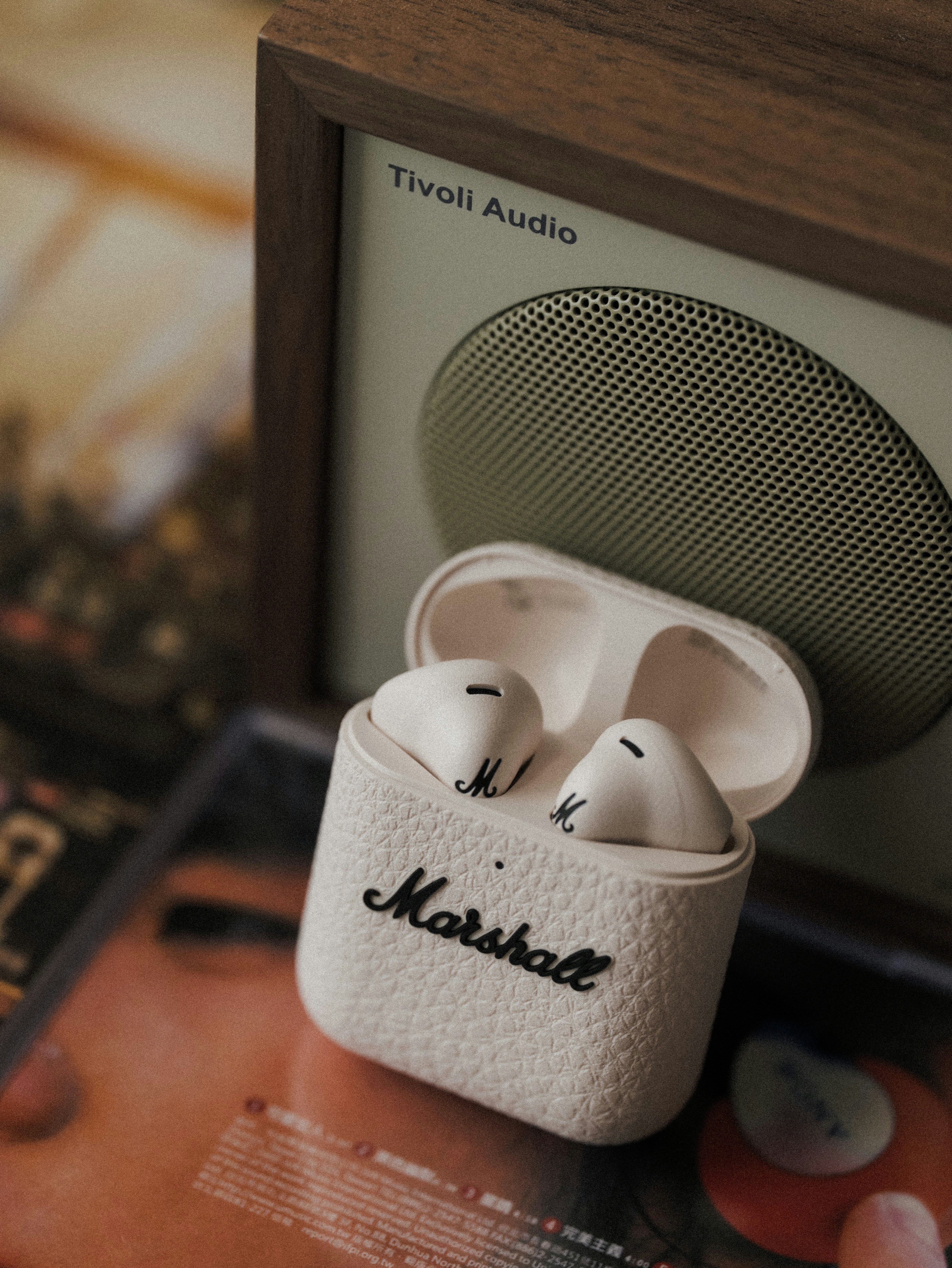 Marshall earbuds in charging case next to tivoli audio speaker