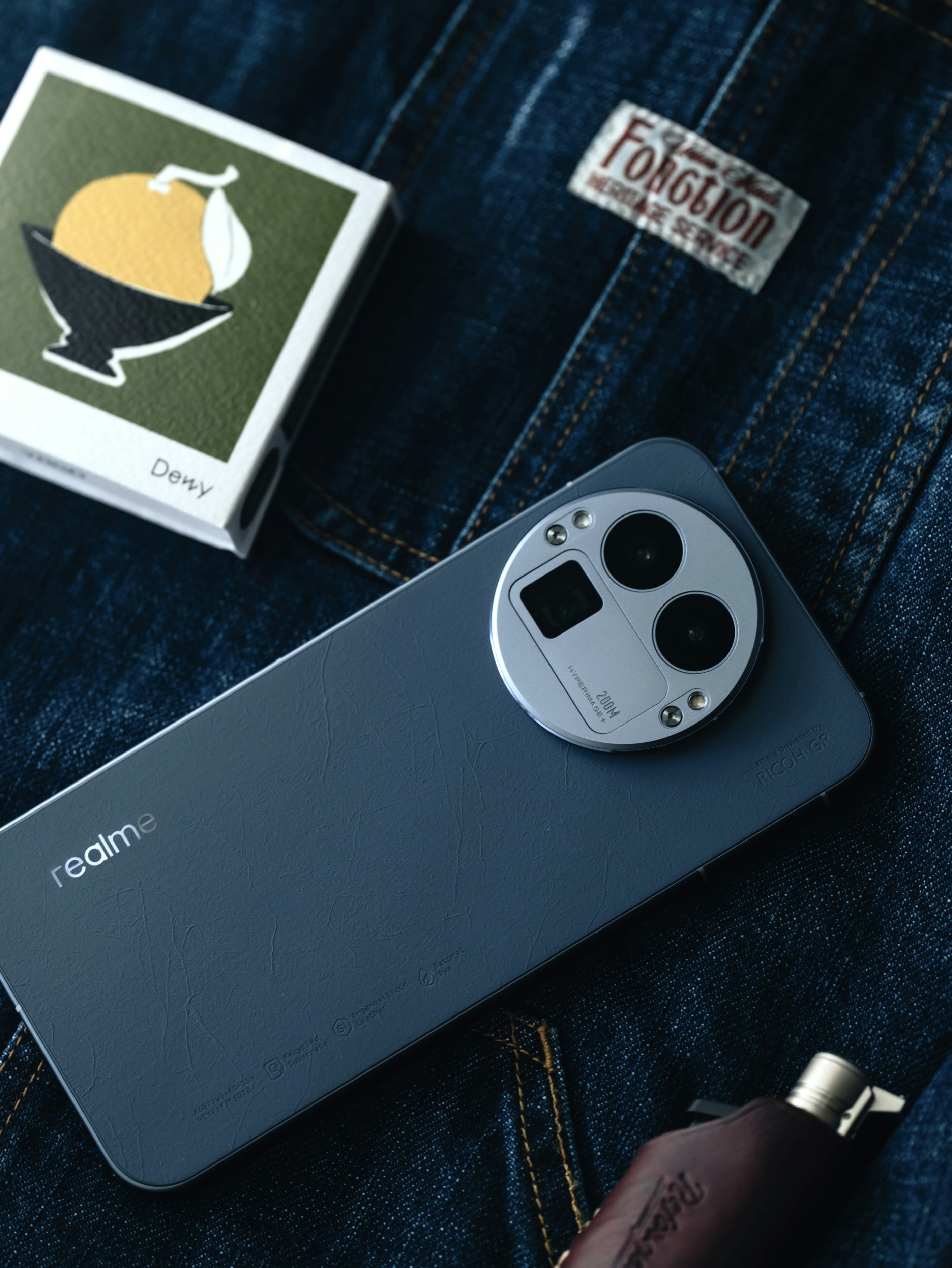 A smartphone rests on a denim surface with accessories.