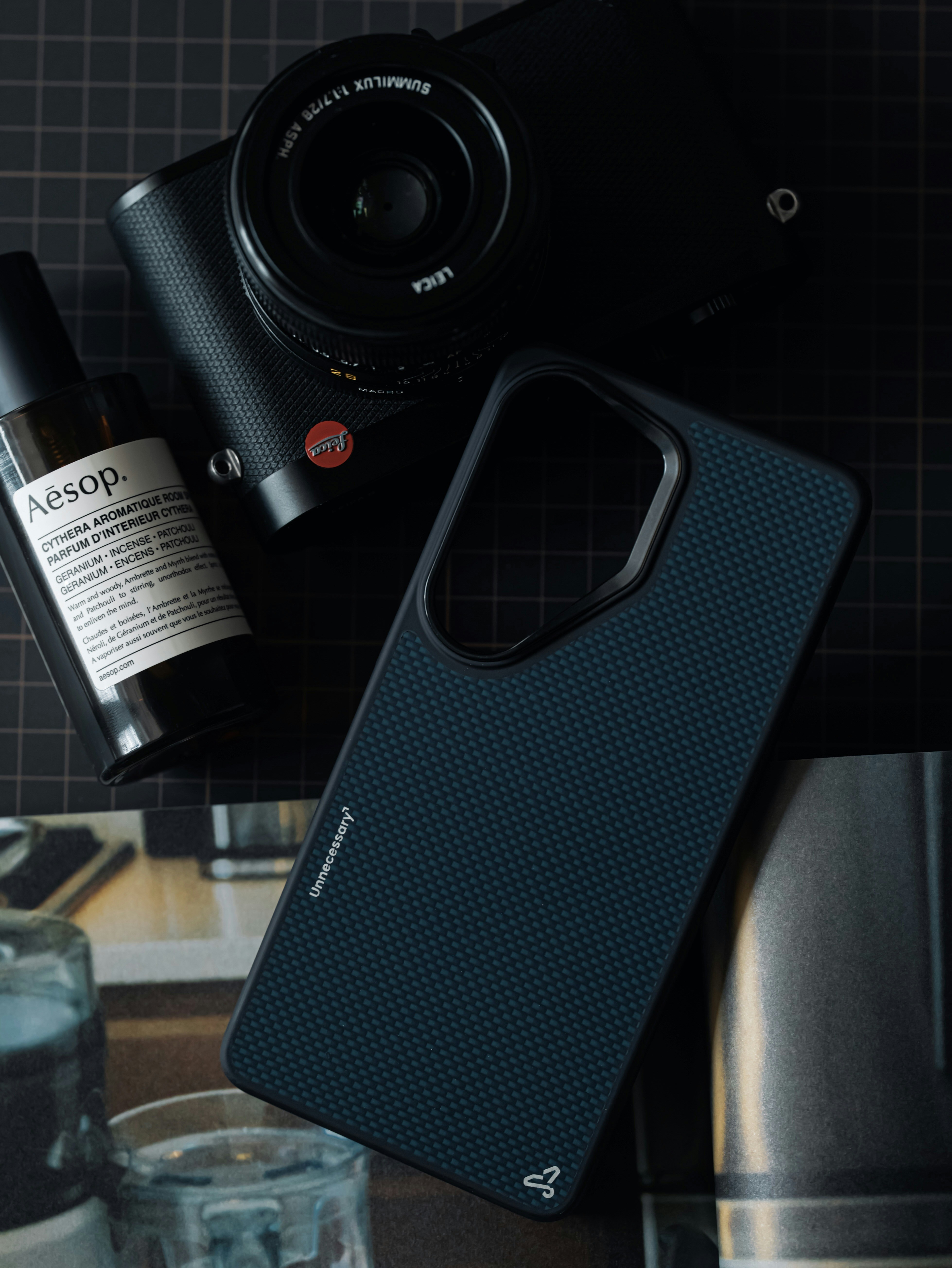 Leica-Style Leica M Moment: A Leica-ish compact with a textured blue case resting beside a vintage lens