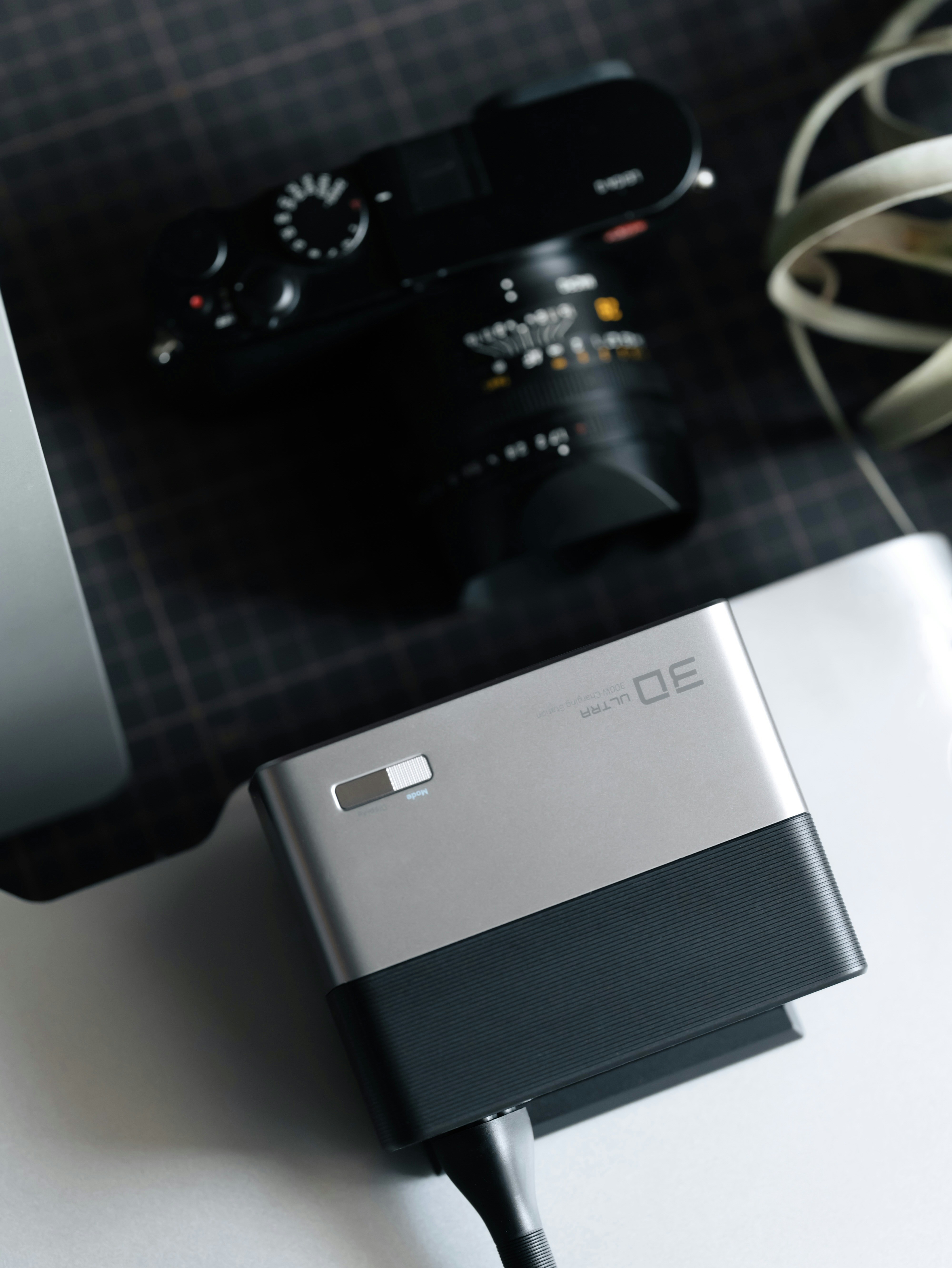 Close‑up of a compact camera perched on a soft plaid backdrop