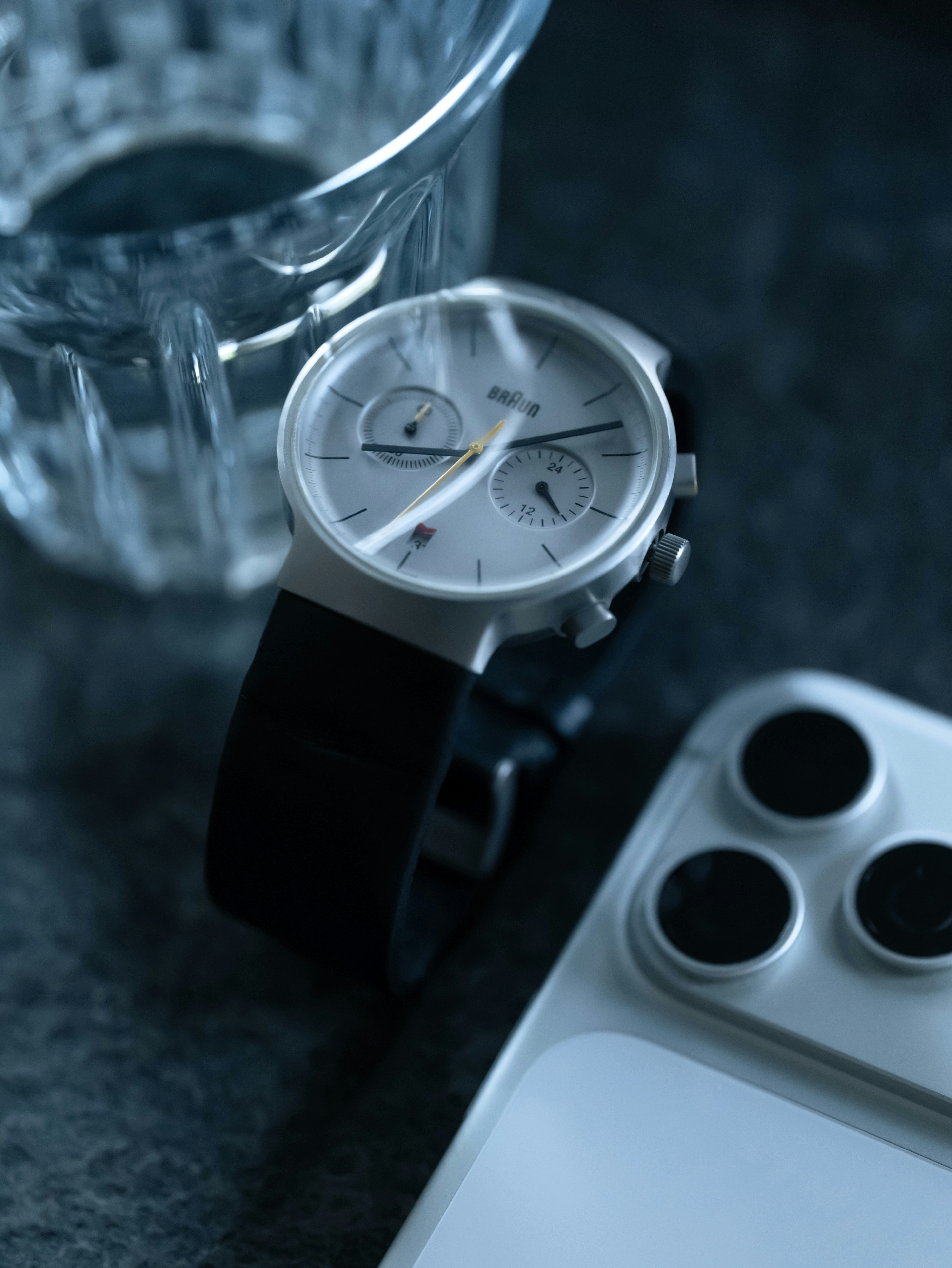 Timekeeper’s Quiet Moment: A Ceramic Watch Resting beside a Glass and Mobile Tray