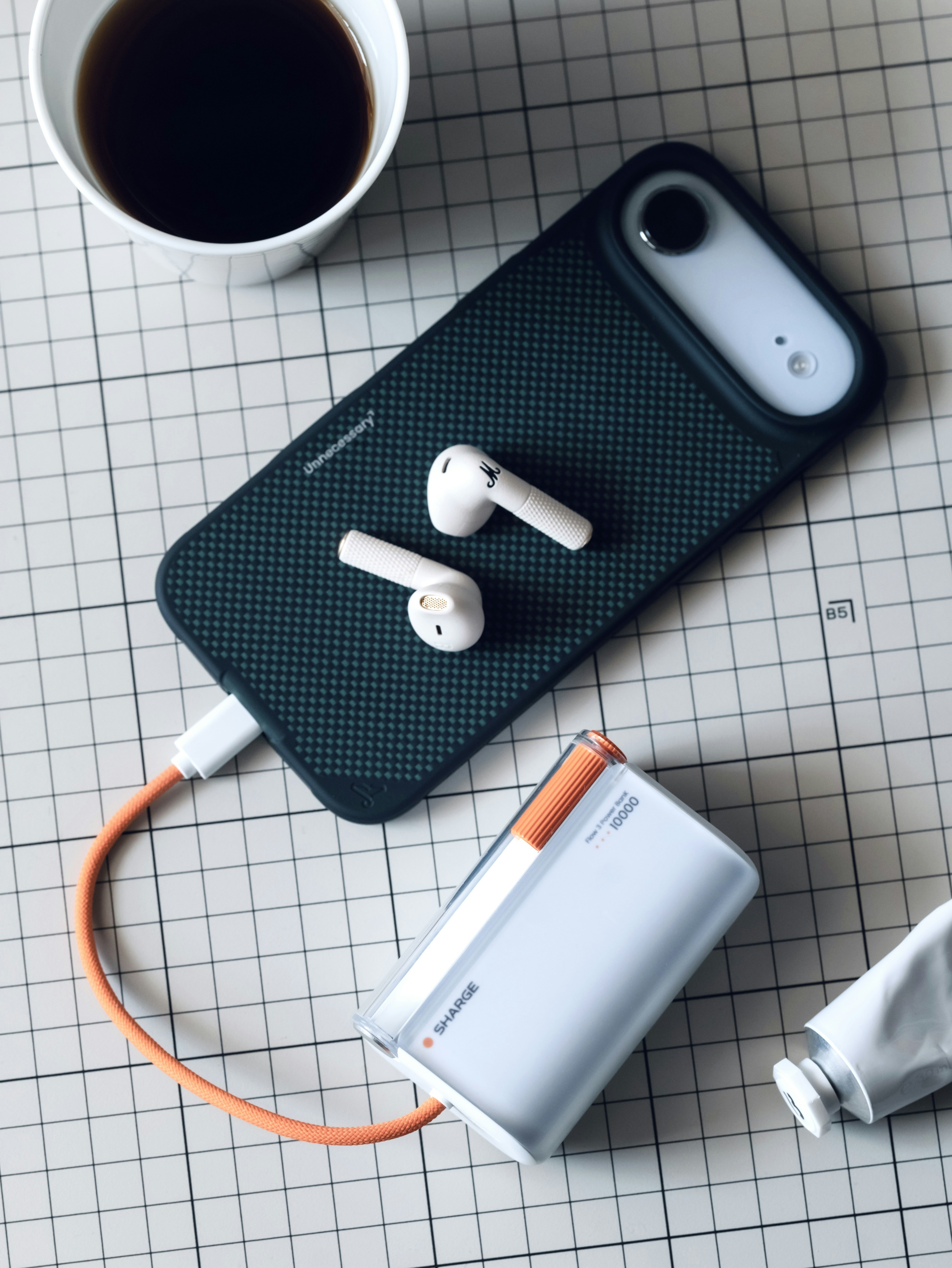 Desk-top Jazz: Wireless Earbuds resting on a textured case beside a coffee cup