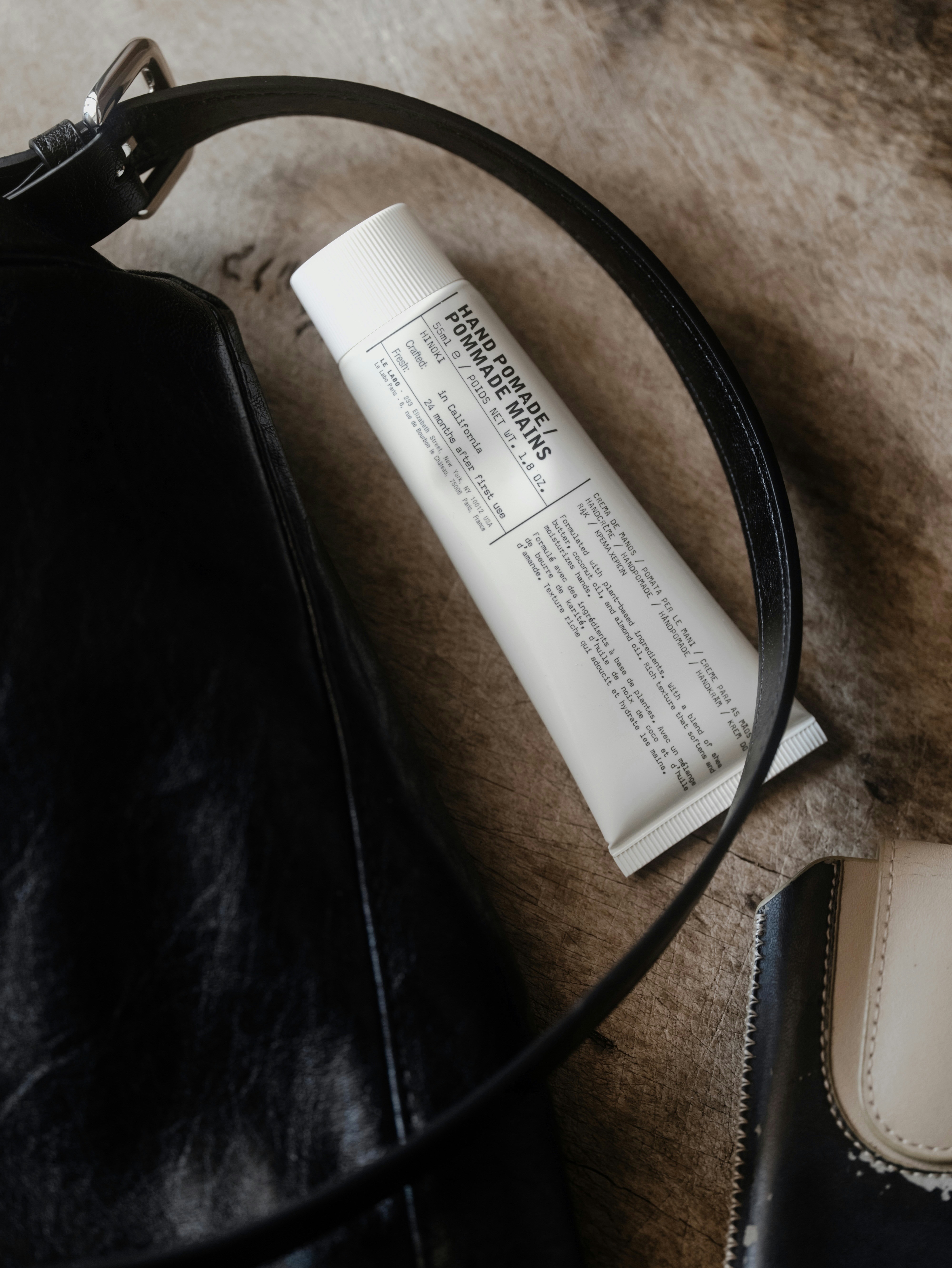 Leather Tote and Tube of Hand Formula Resting on a Plush Surface