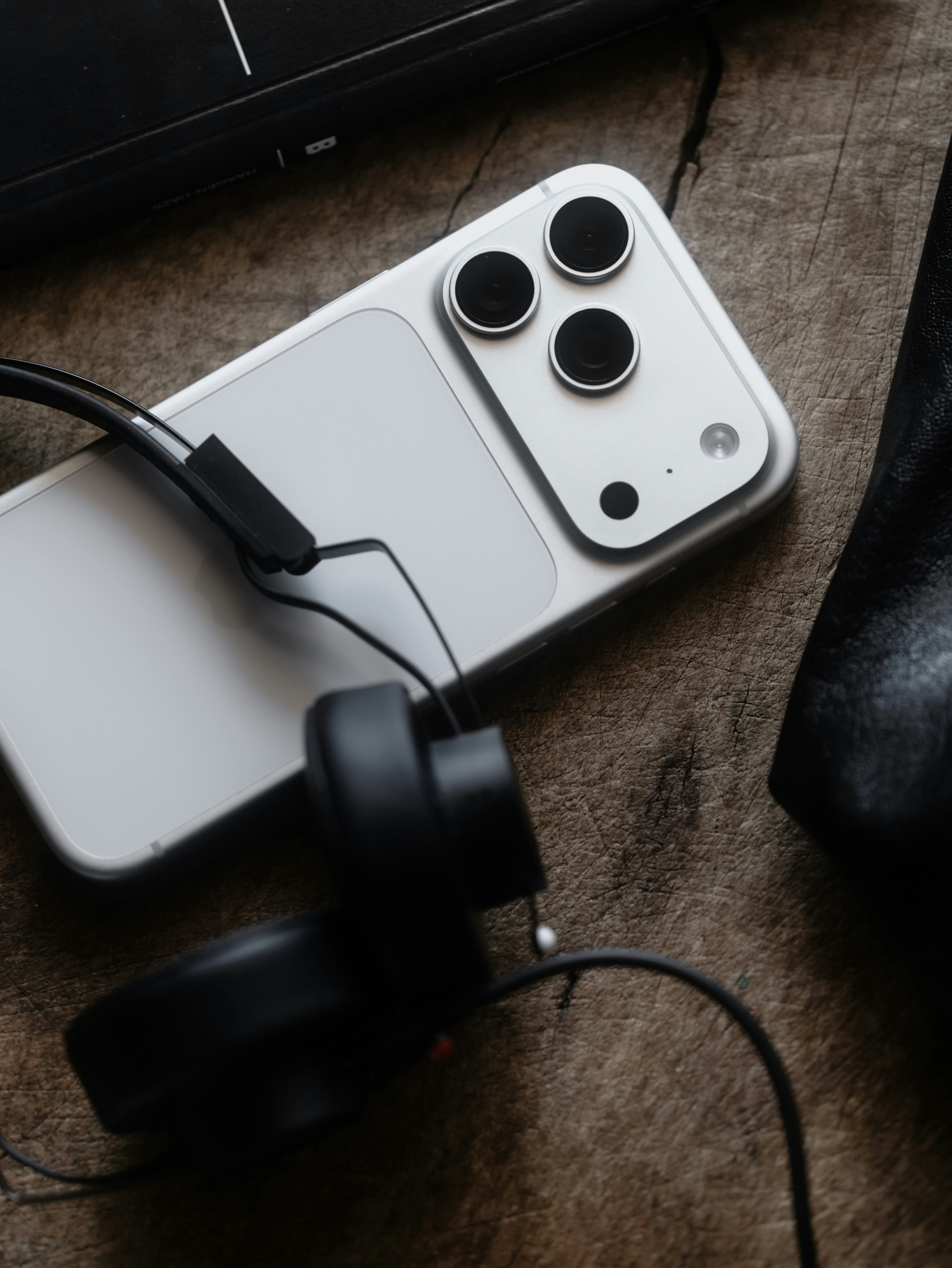 Lensed Echoes: A White iPhone and Headphones on Weathered Wood