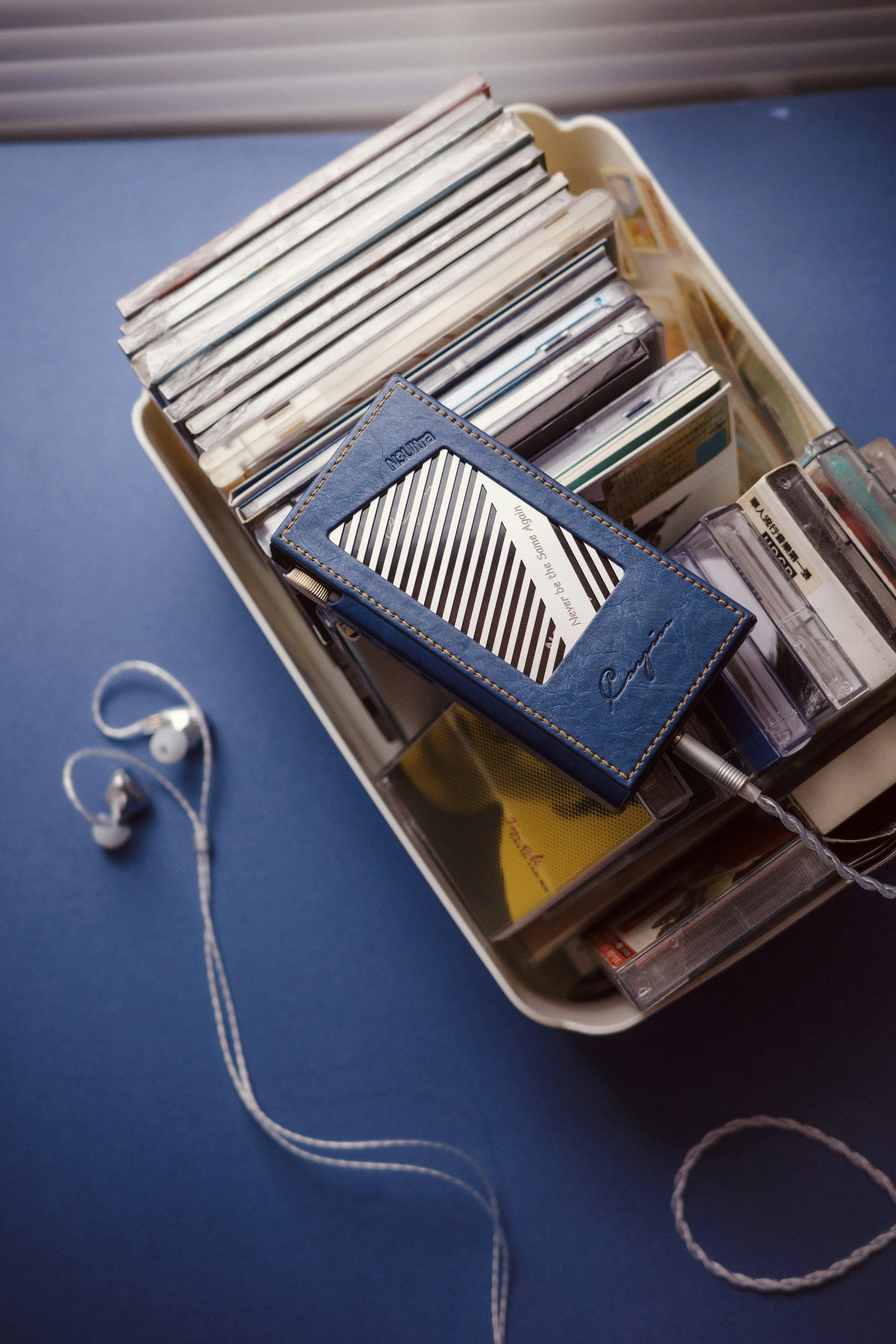 Blue leather cardholder resting among a vintage cassette case