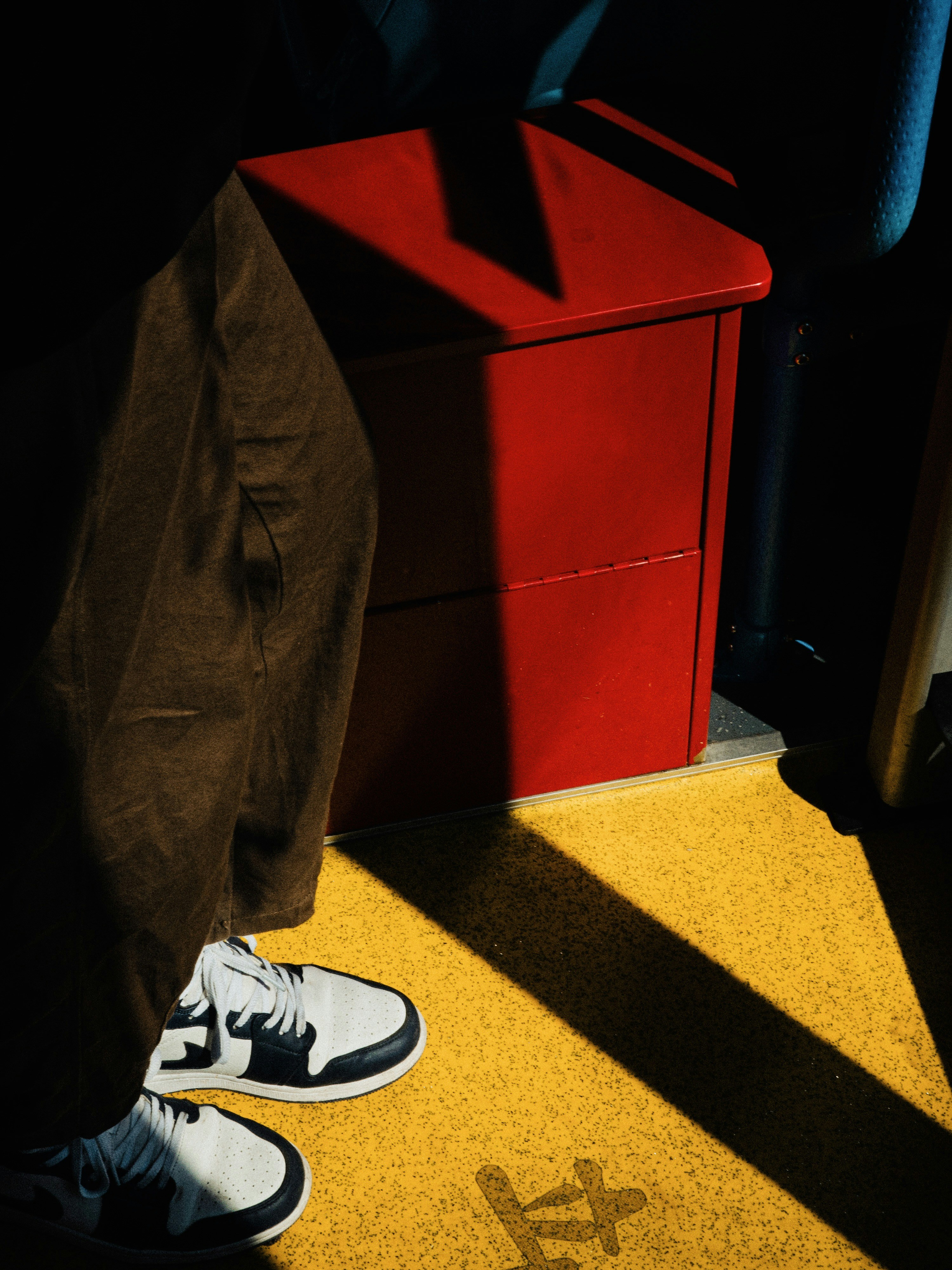 Shadowed Corner: Red Drawer, Neon Shoes, and Sunlit Floor