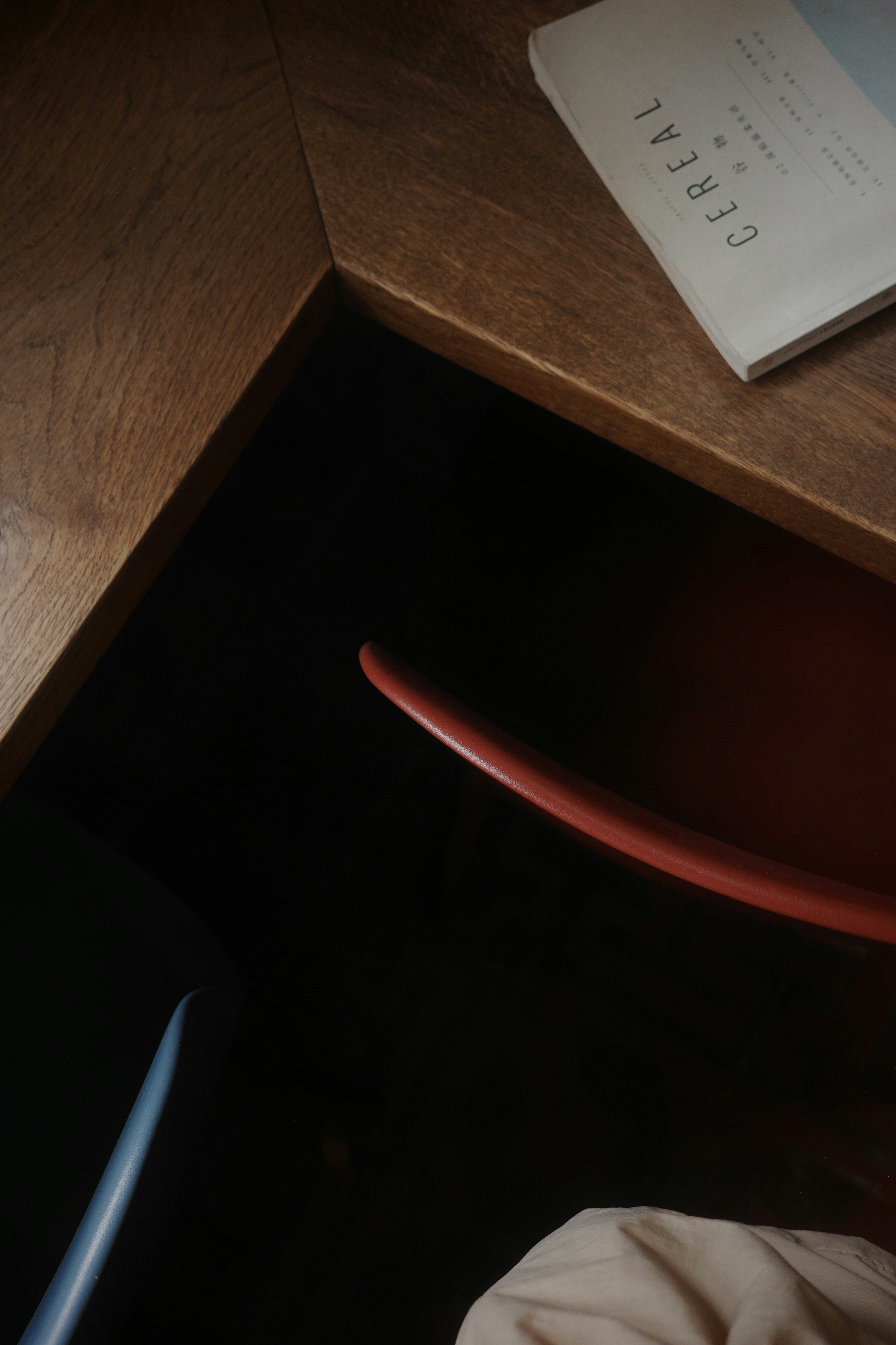 Underlit Corner: A Quiet Desk with a Book on Woodgrain Surface