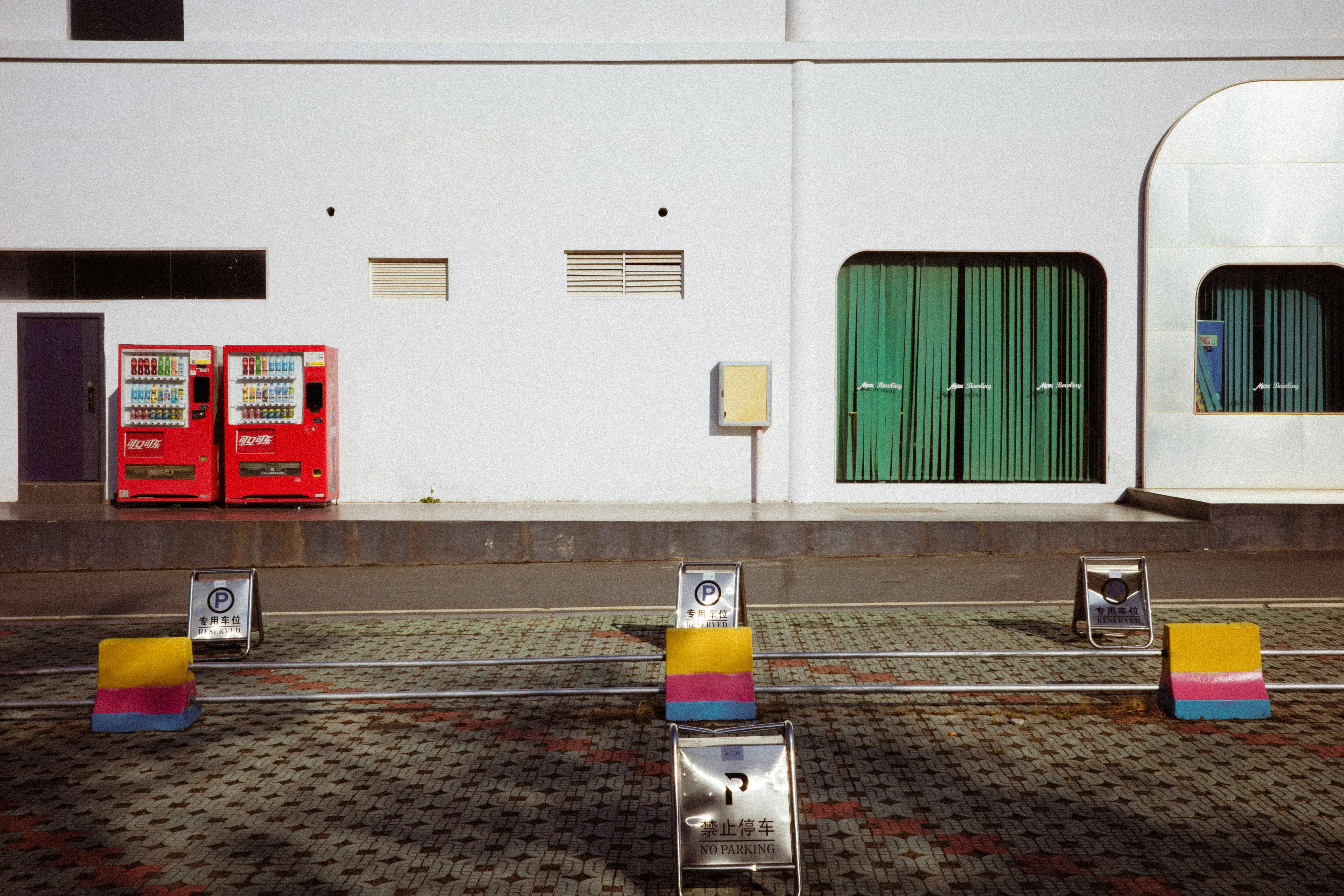 Two red vending machines stand by a white wall.