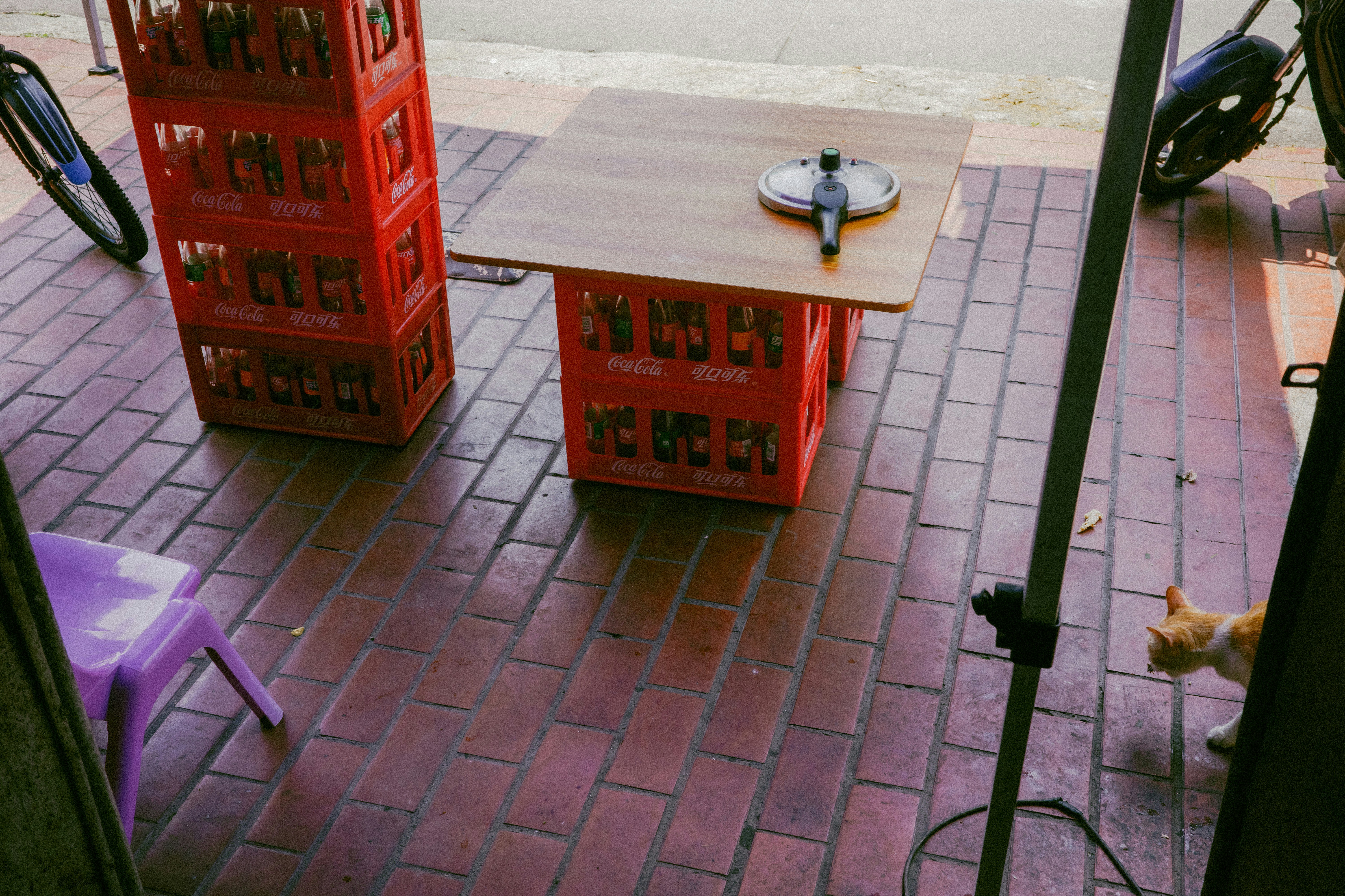 A Quiet Street Café Perch: Red Crates as Tables and a Cat at the Edge
