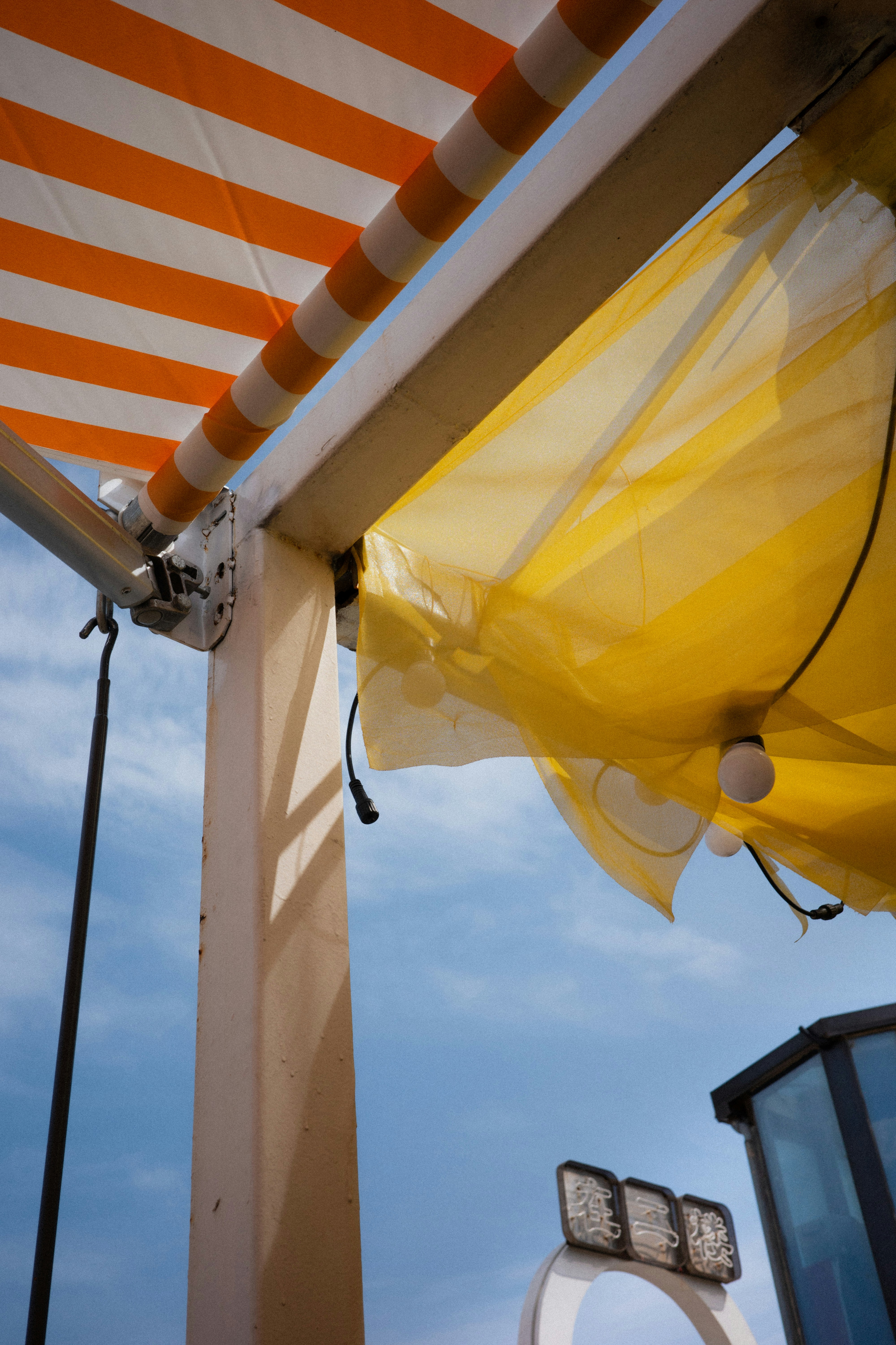 Diagonal Canopy and Yellow Textile at a Sunny Stand