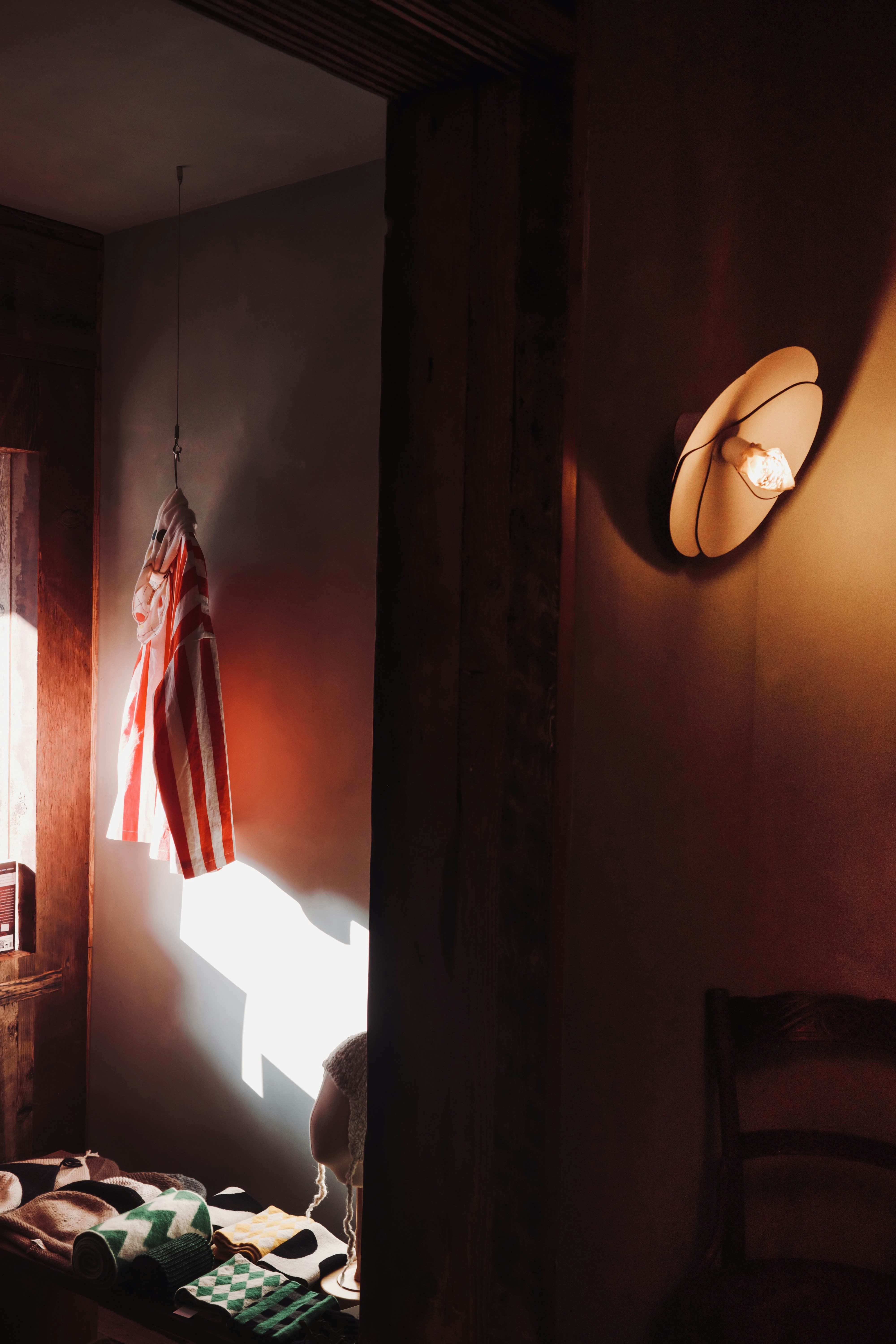 Muted Sunlit Corner: A Hanging Shirt and Warm Wall Light