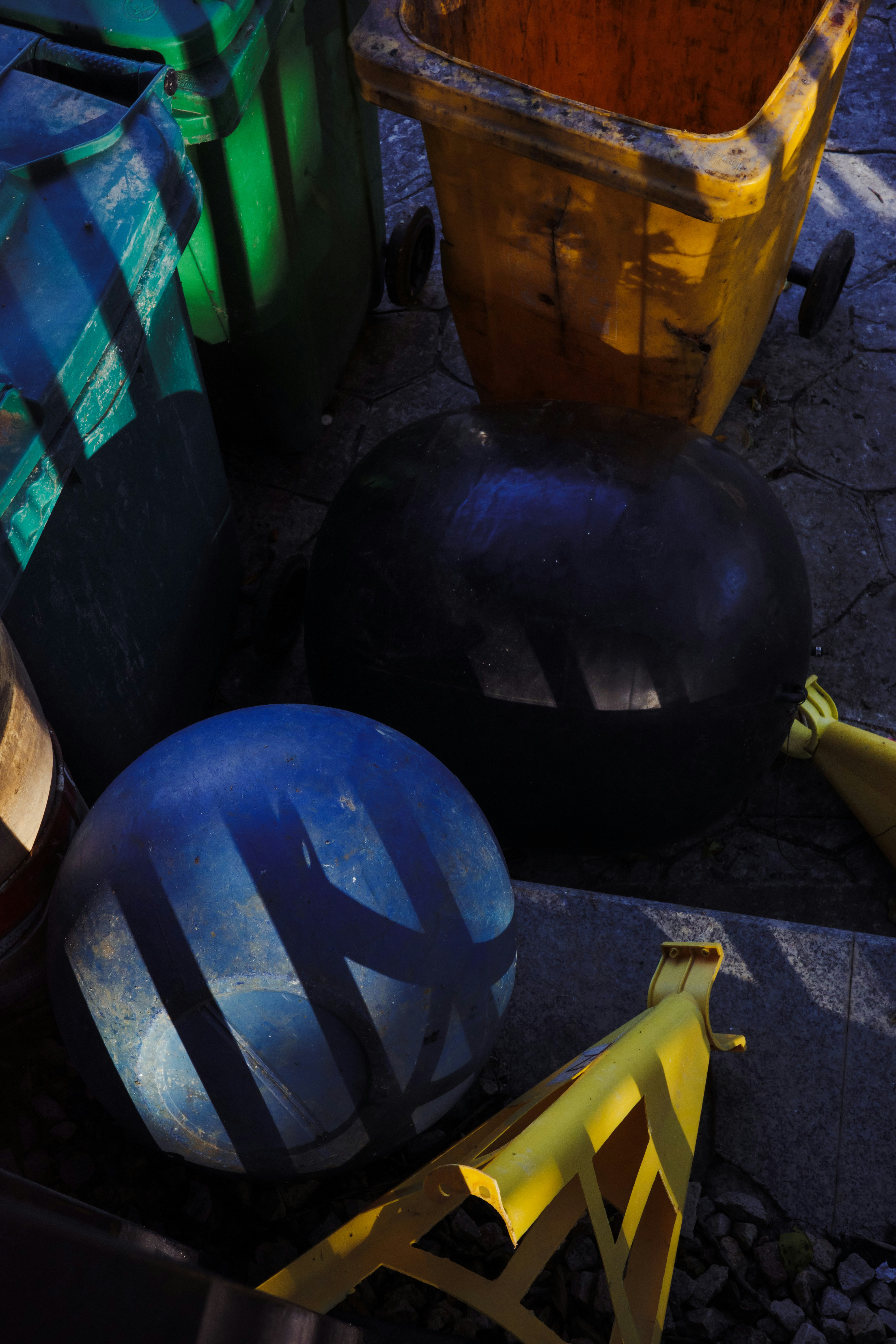 Colorful Waste Bins and Urban Debris in Dappled Light