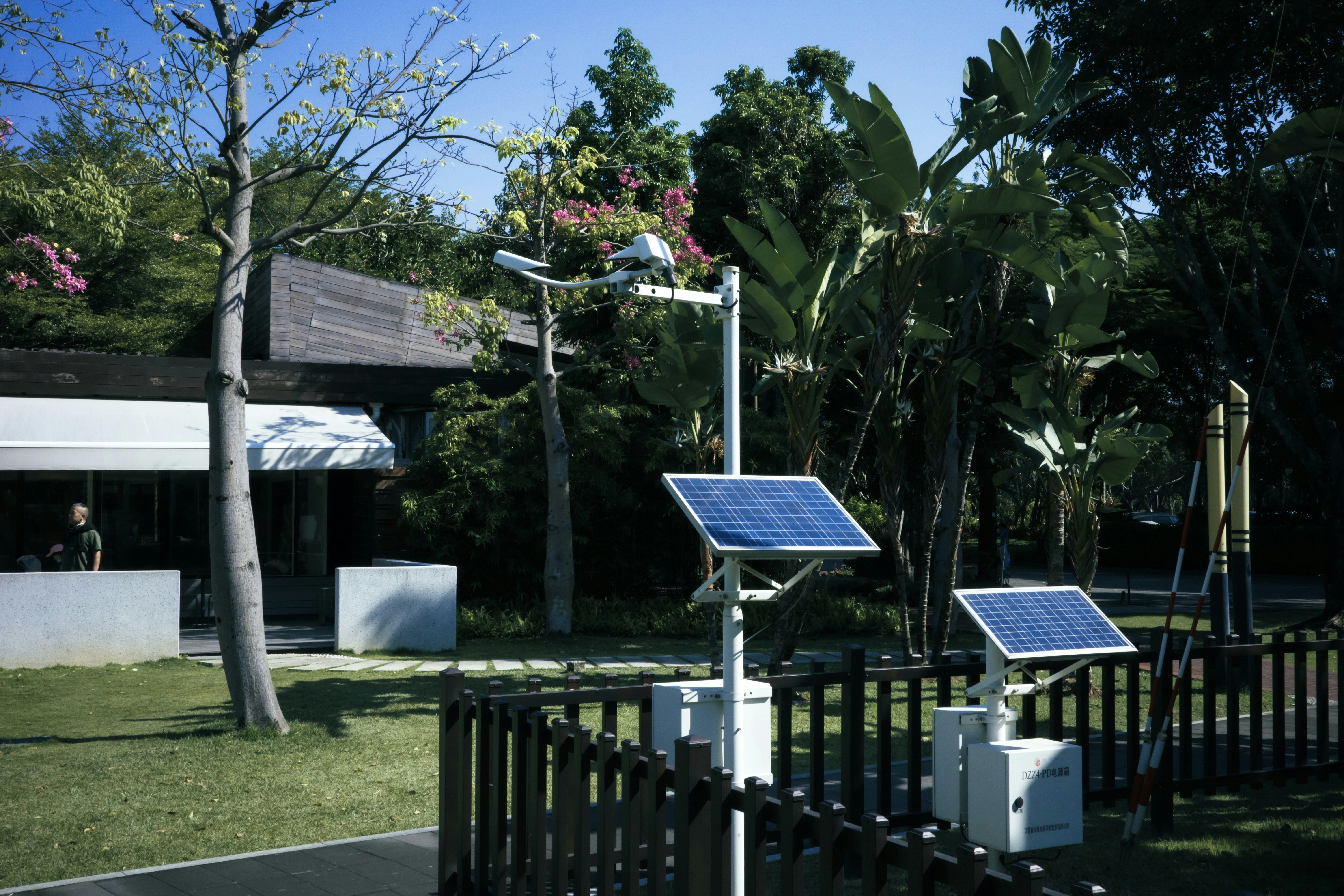 Two solar panels stand in a grassy park area.