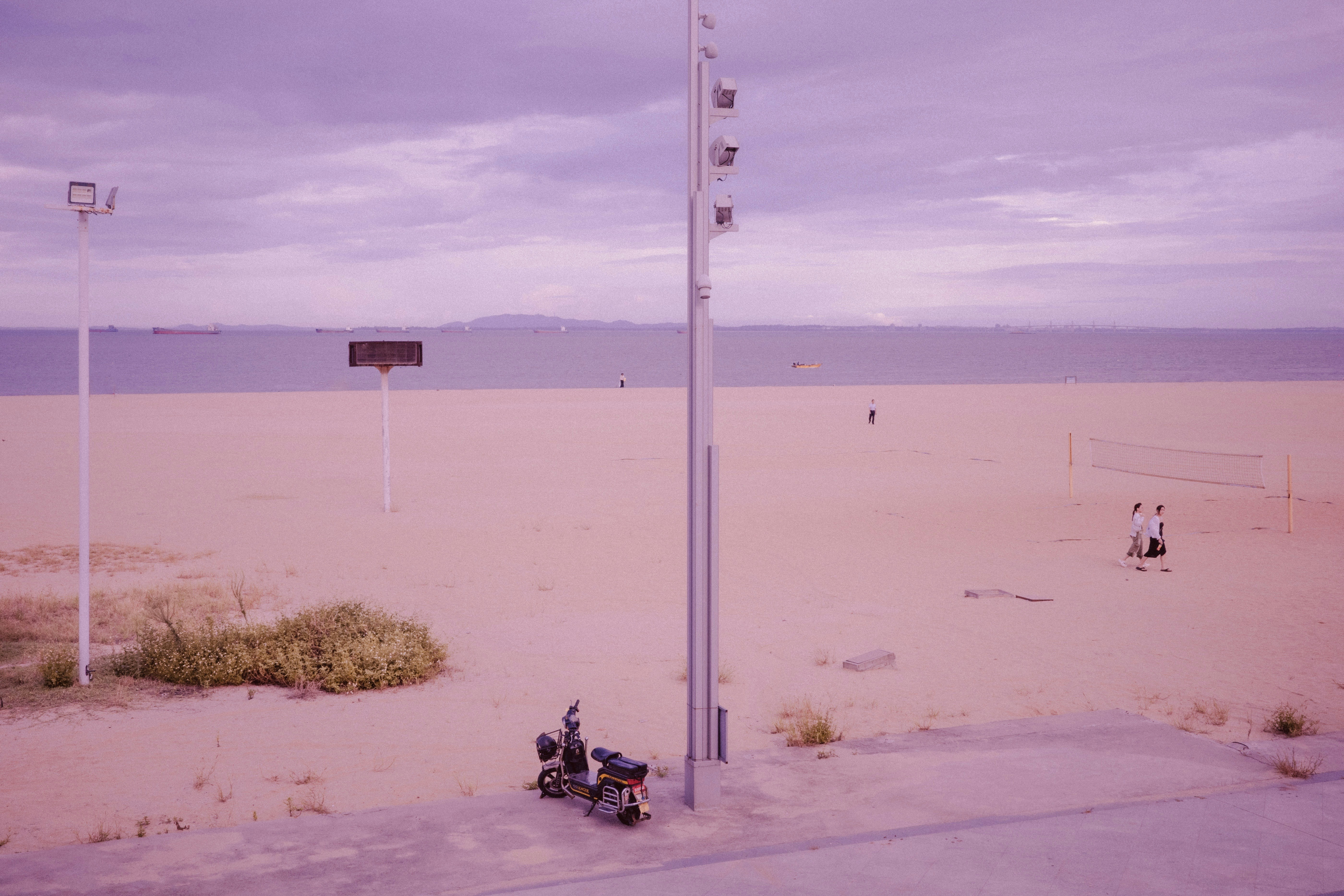 Quiet Beachfront with Distant Silhouettes under a Lavender Sky