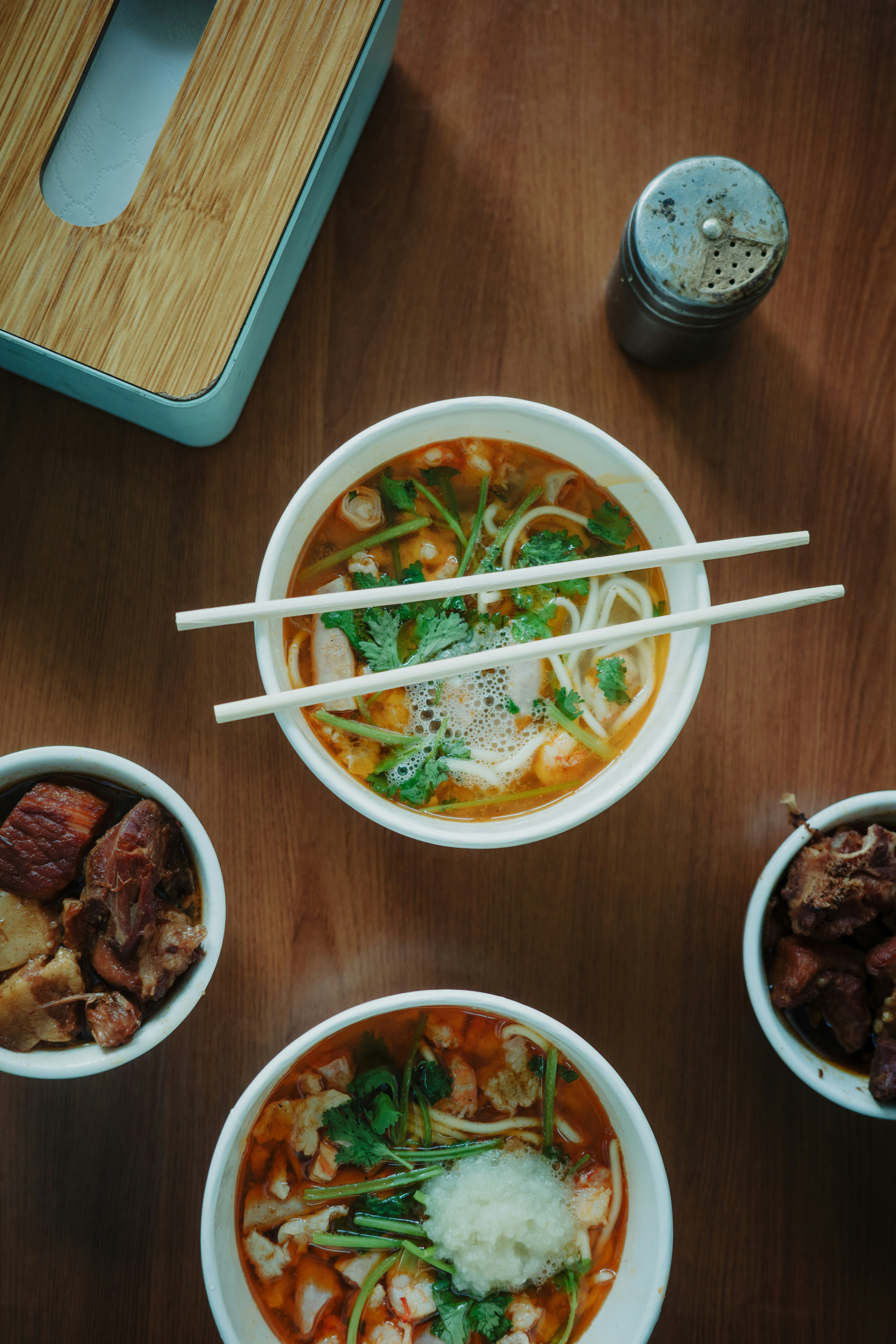 Noodle Bowls on a Wooden Table — Steam, Garnish, and Chopsticks