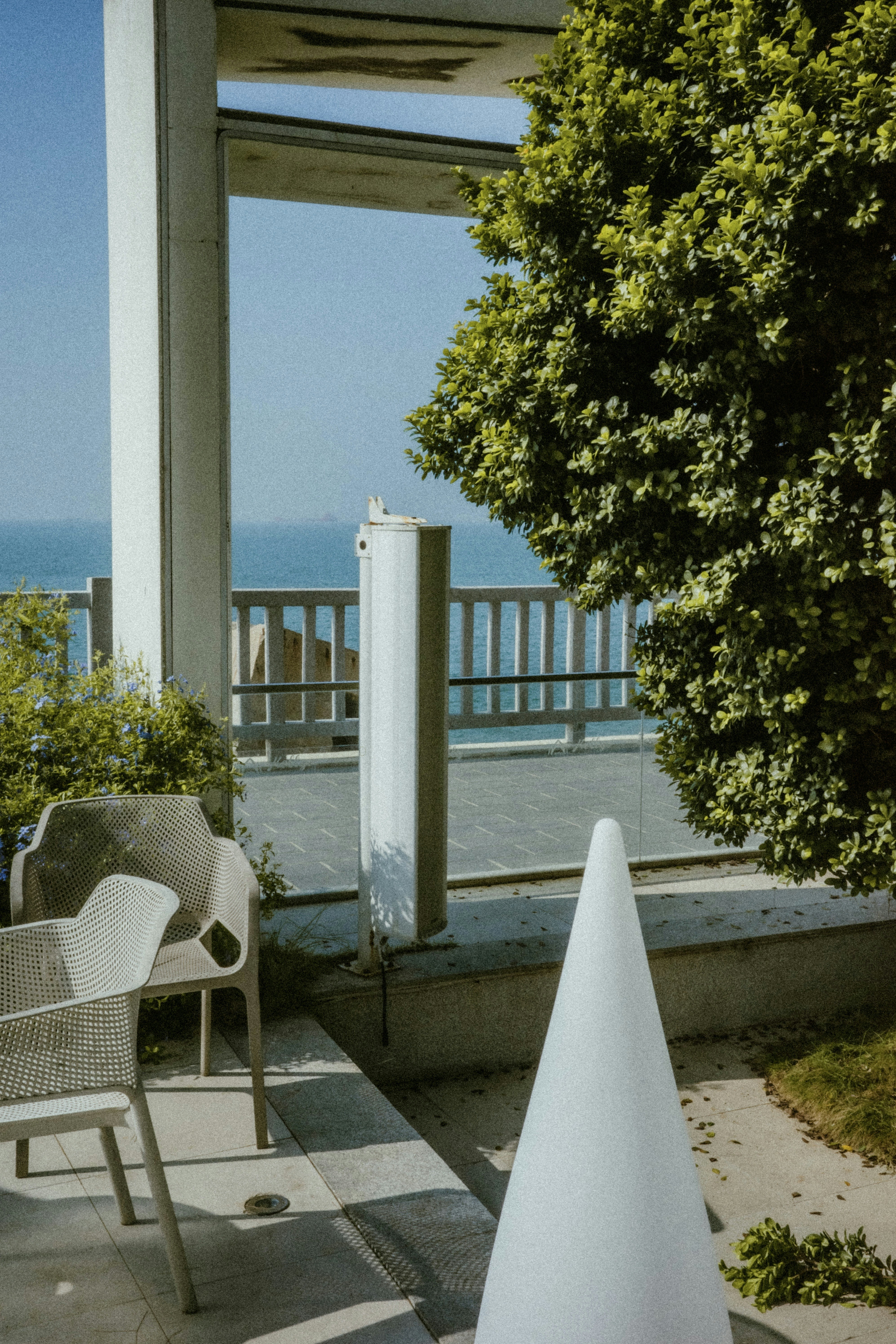 Sunlit Terrace Overlooking the Sea with Modern Mast and Cone Sculpture