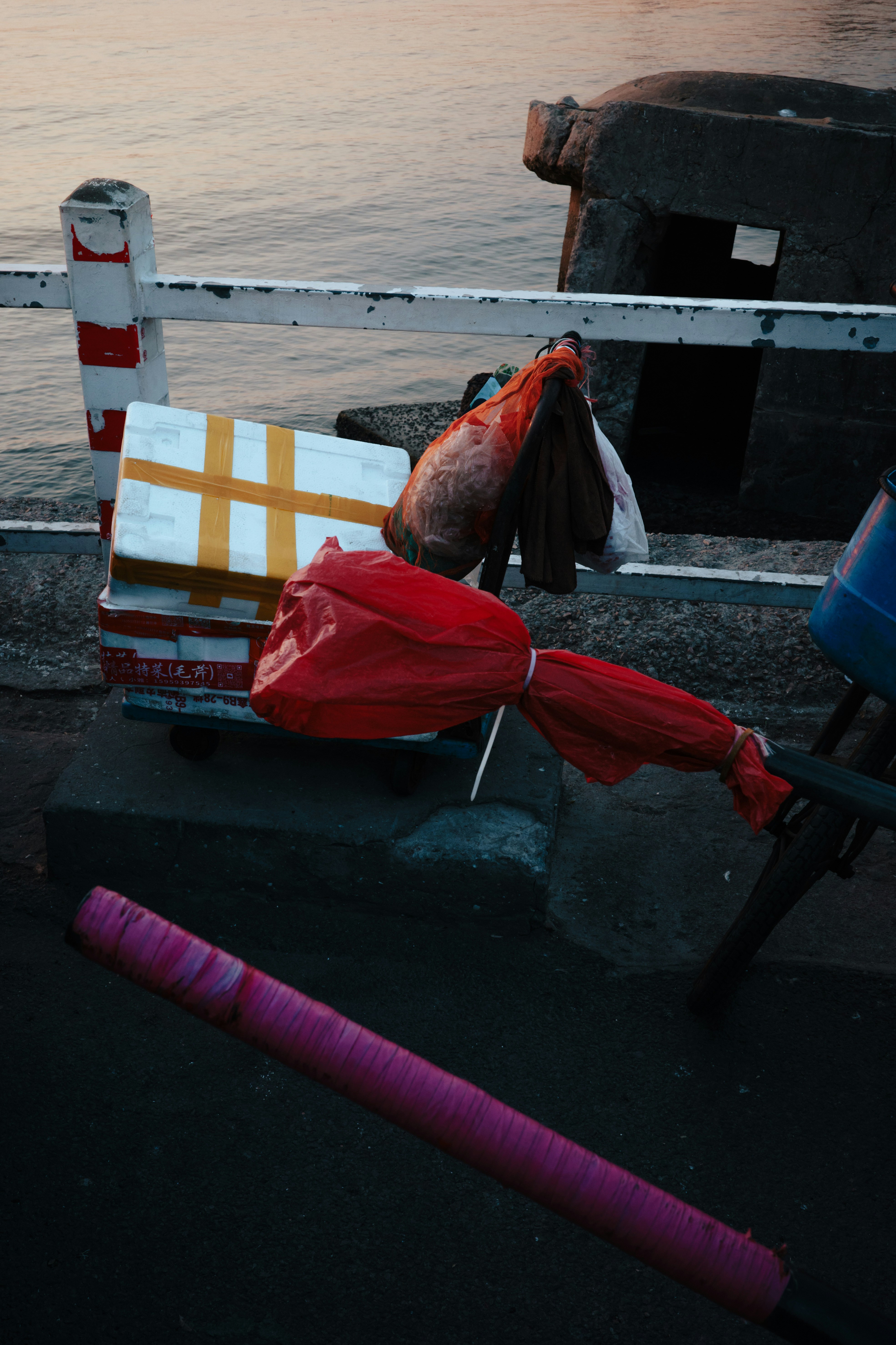 Fishing pole and packages on a dock at dusk.