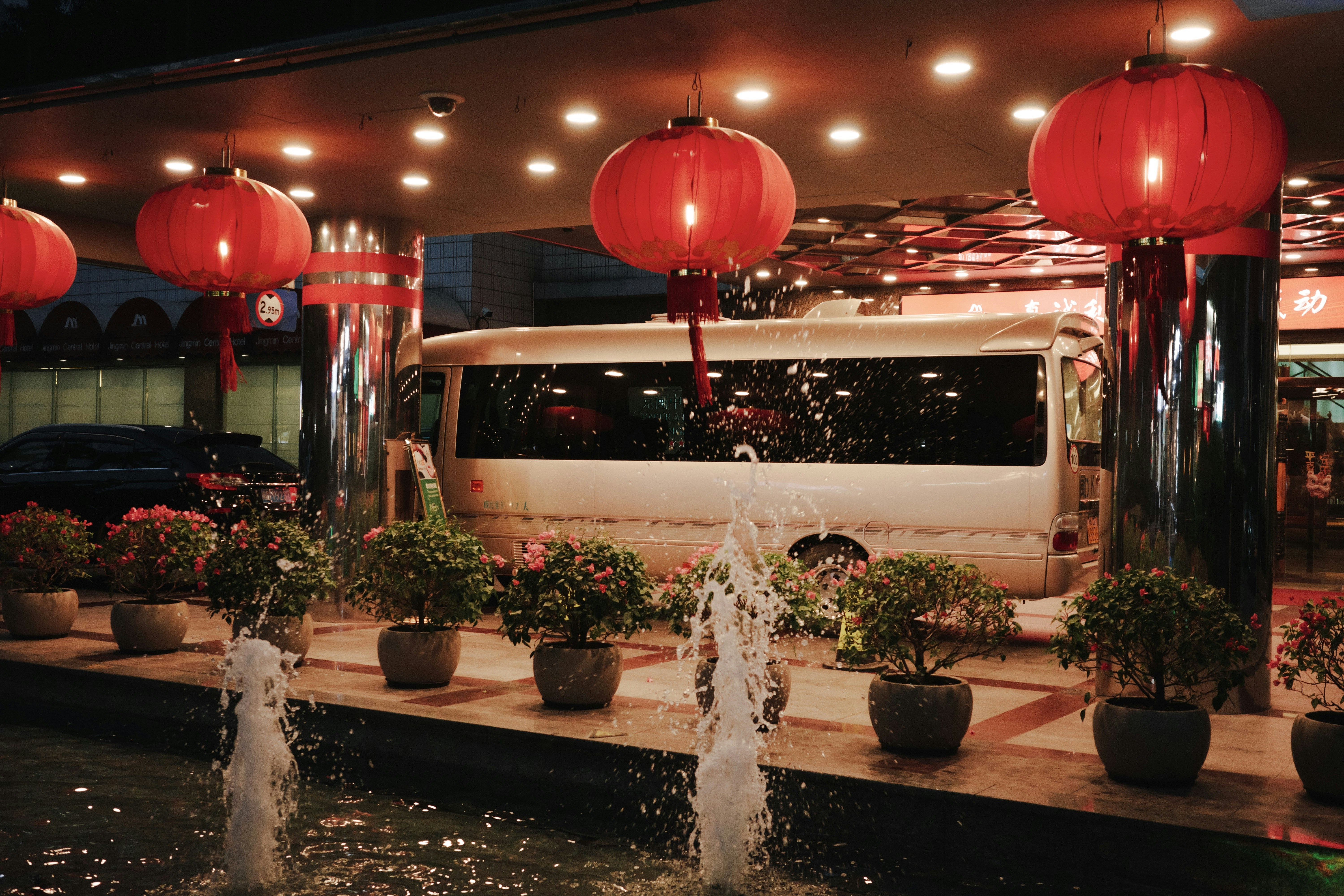 Red Lanterns, White Van, and Water Jets at a Night Drive-Through Entrance
