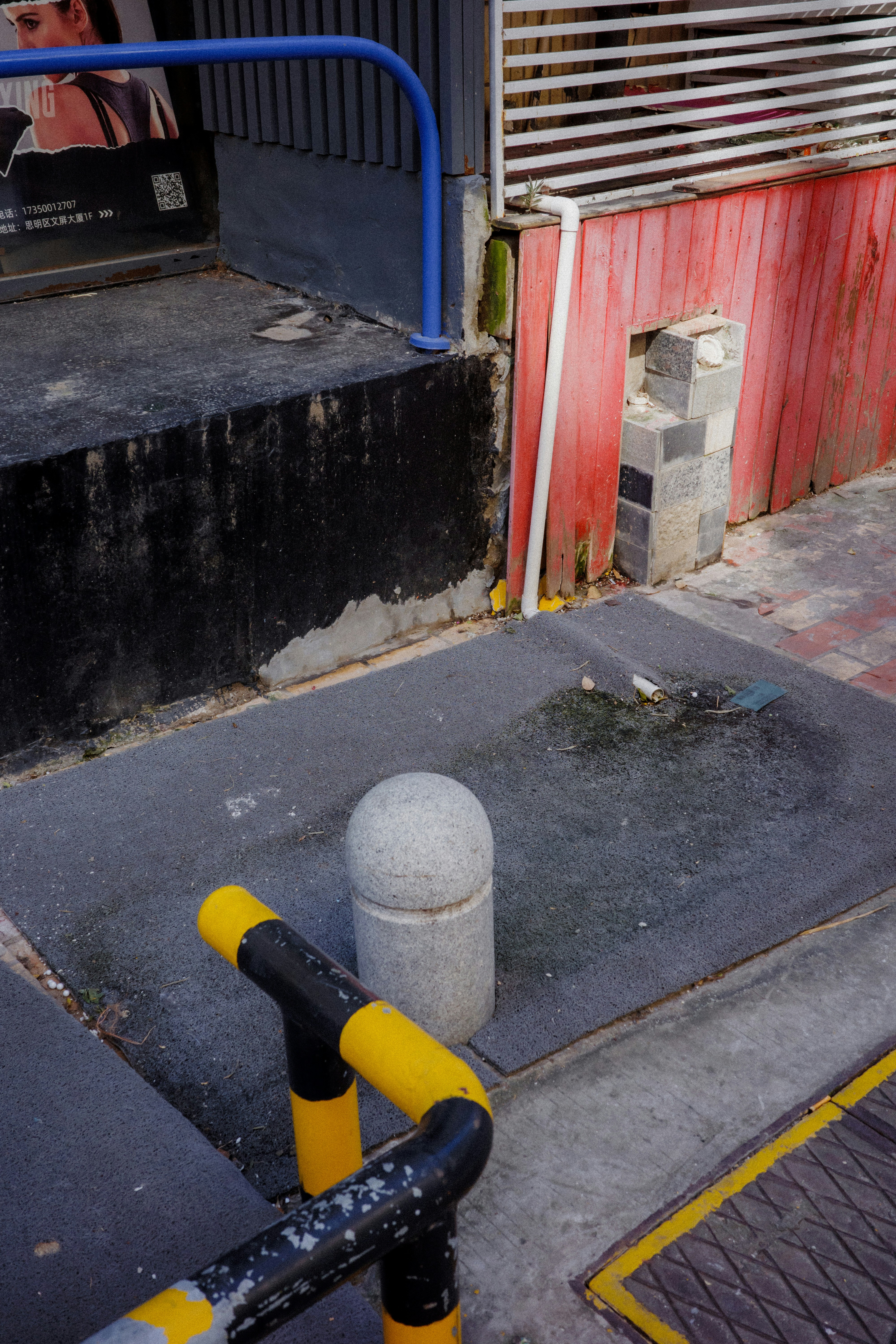 Urban curbside geometry: yellow and black railings frame a concrete bollard