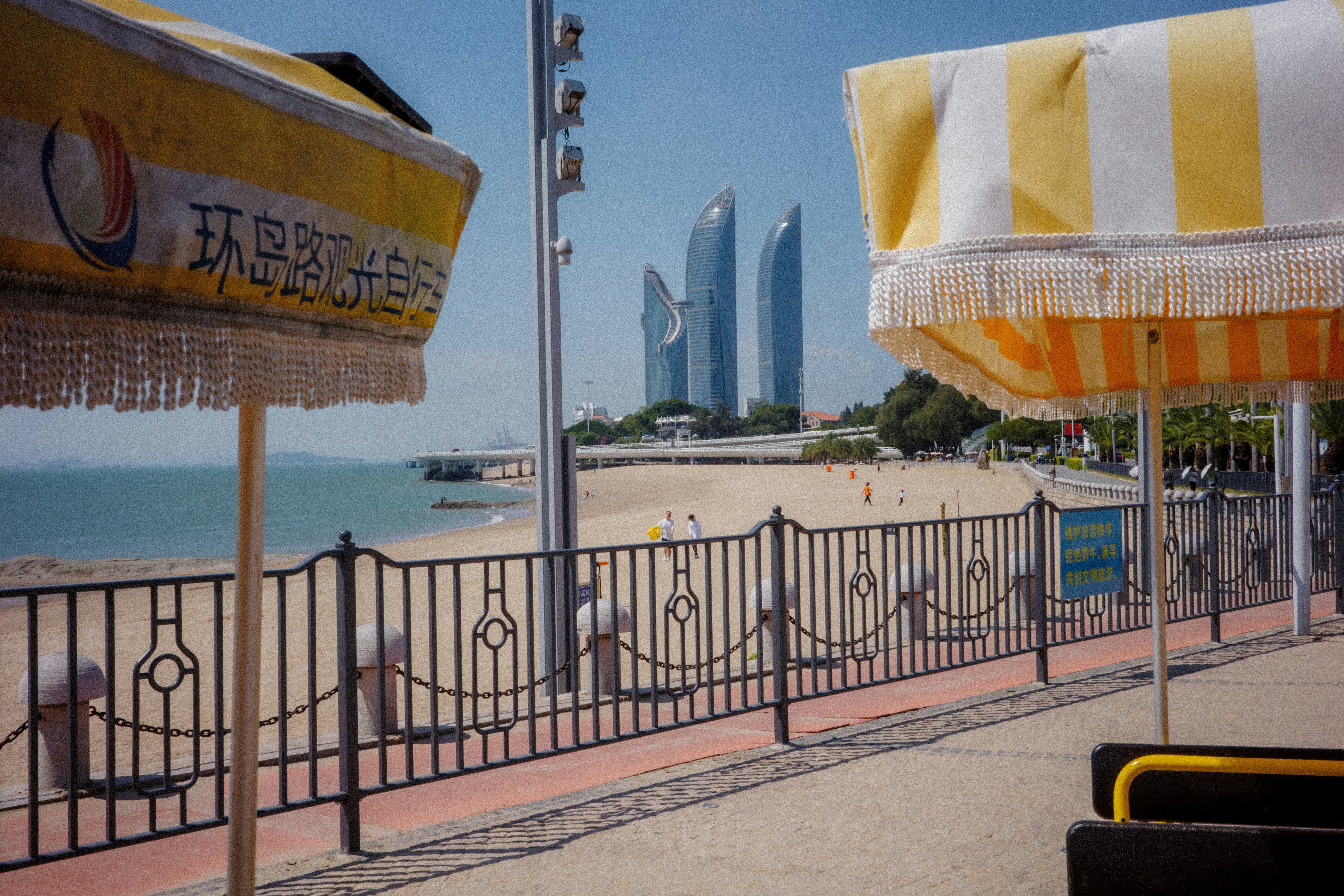 Promenade Perspective: Skyscrapers Rise Over a Shaded Beachfront