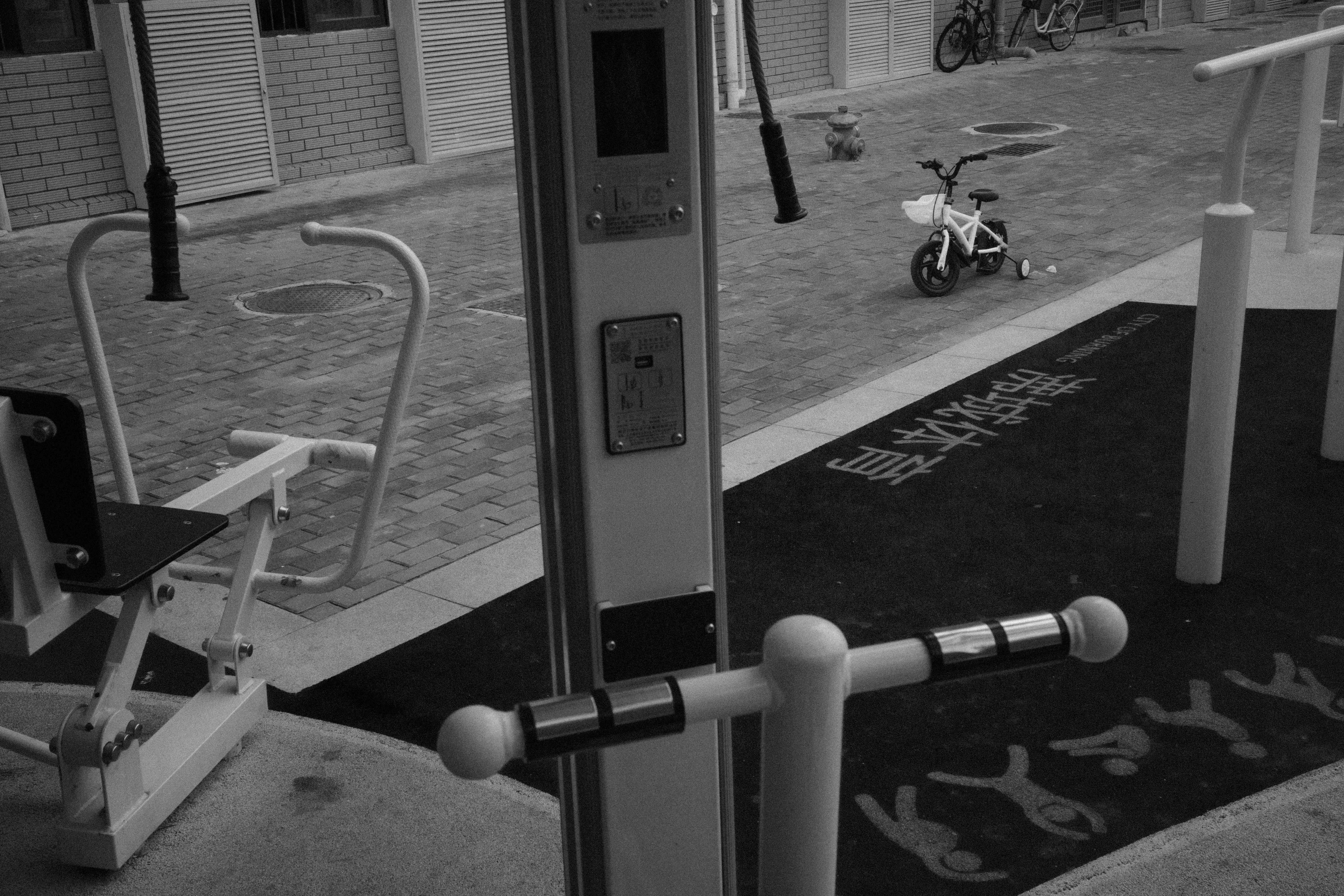 Quiet Gym Corner: Outdoor Fitness Equipment Framed by Urban Pathway