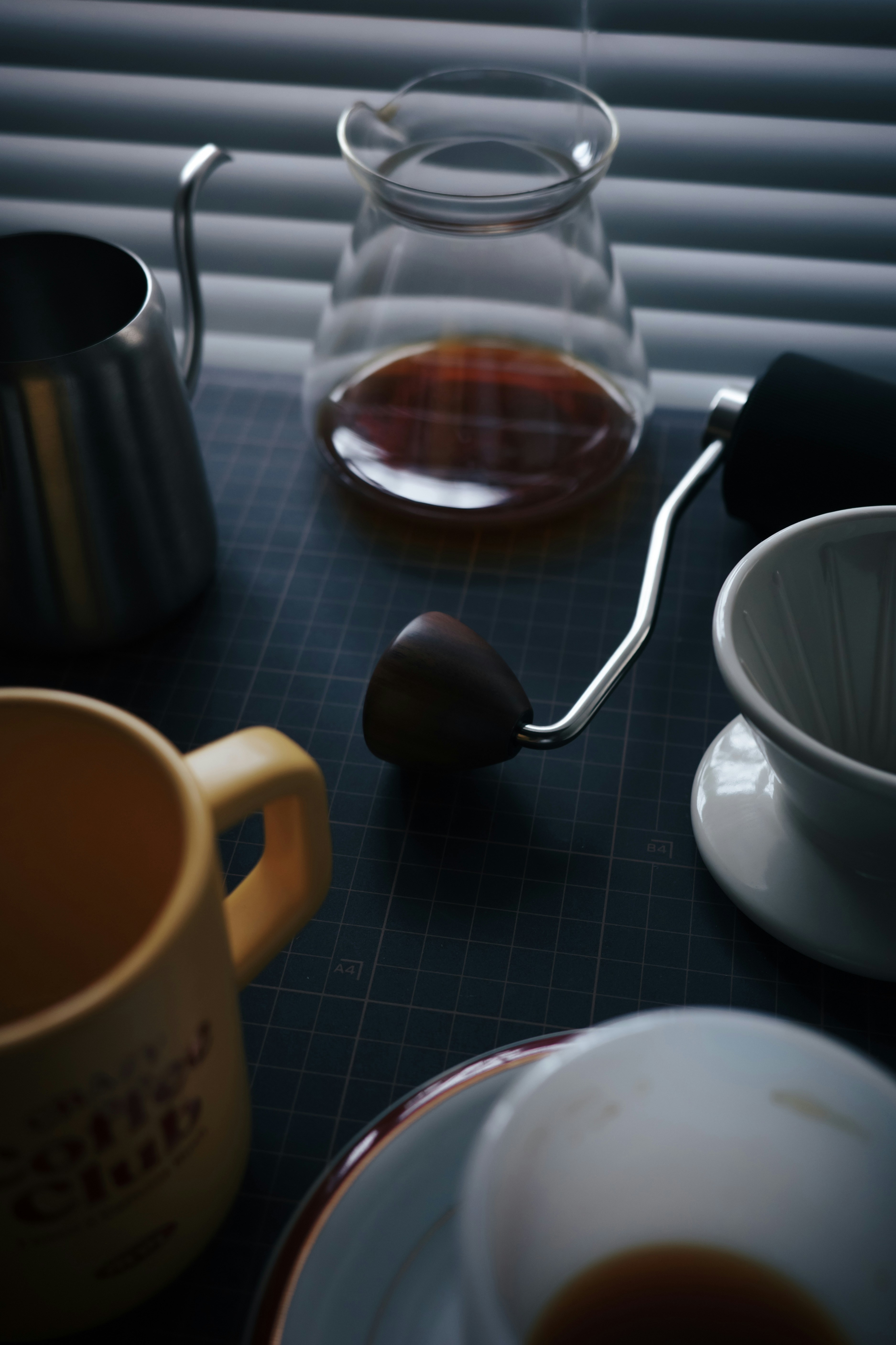 A Quiet Barista Station: Glass Carafe and Drip Gear on a Grid Mat