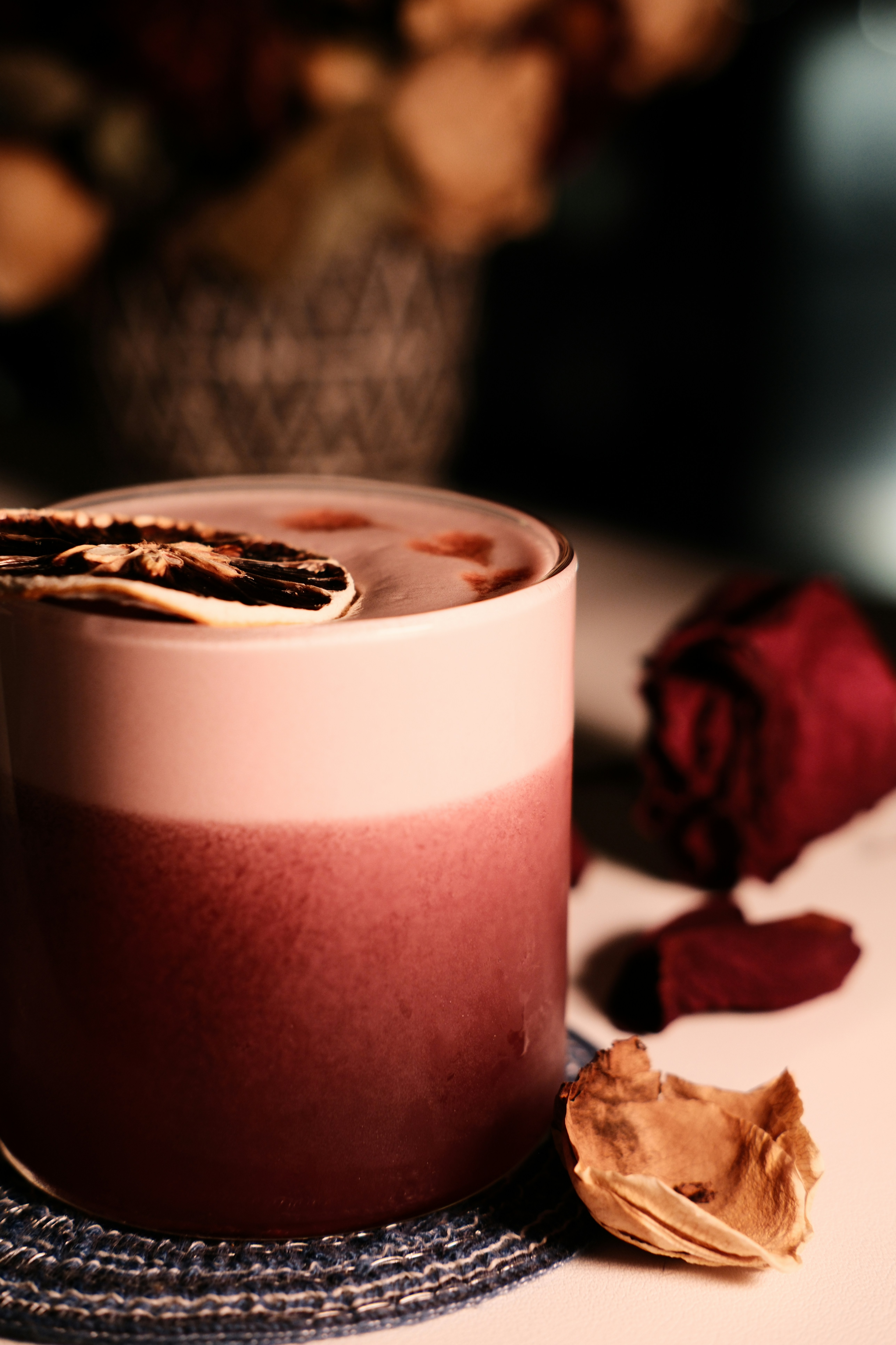 Velvet Dawn: A Cocoa-Hued Cocktail with Dried Citrus on a Rose-Tinted Surface