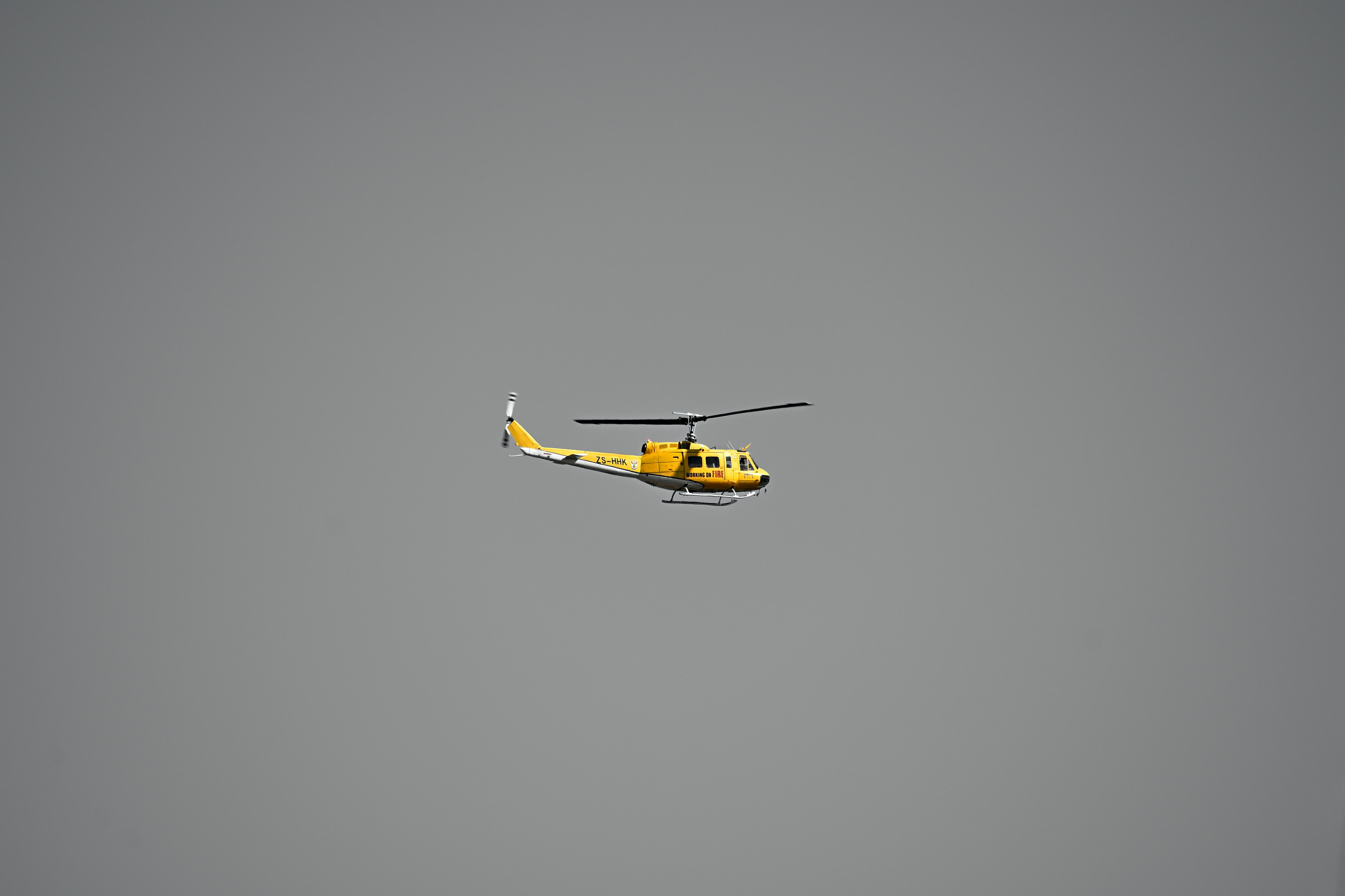 Yellow Rescue Helicopter Drifts Across Gray Sky