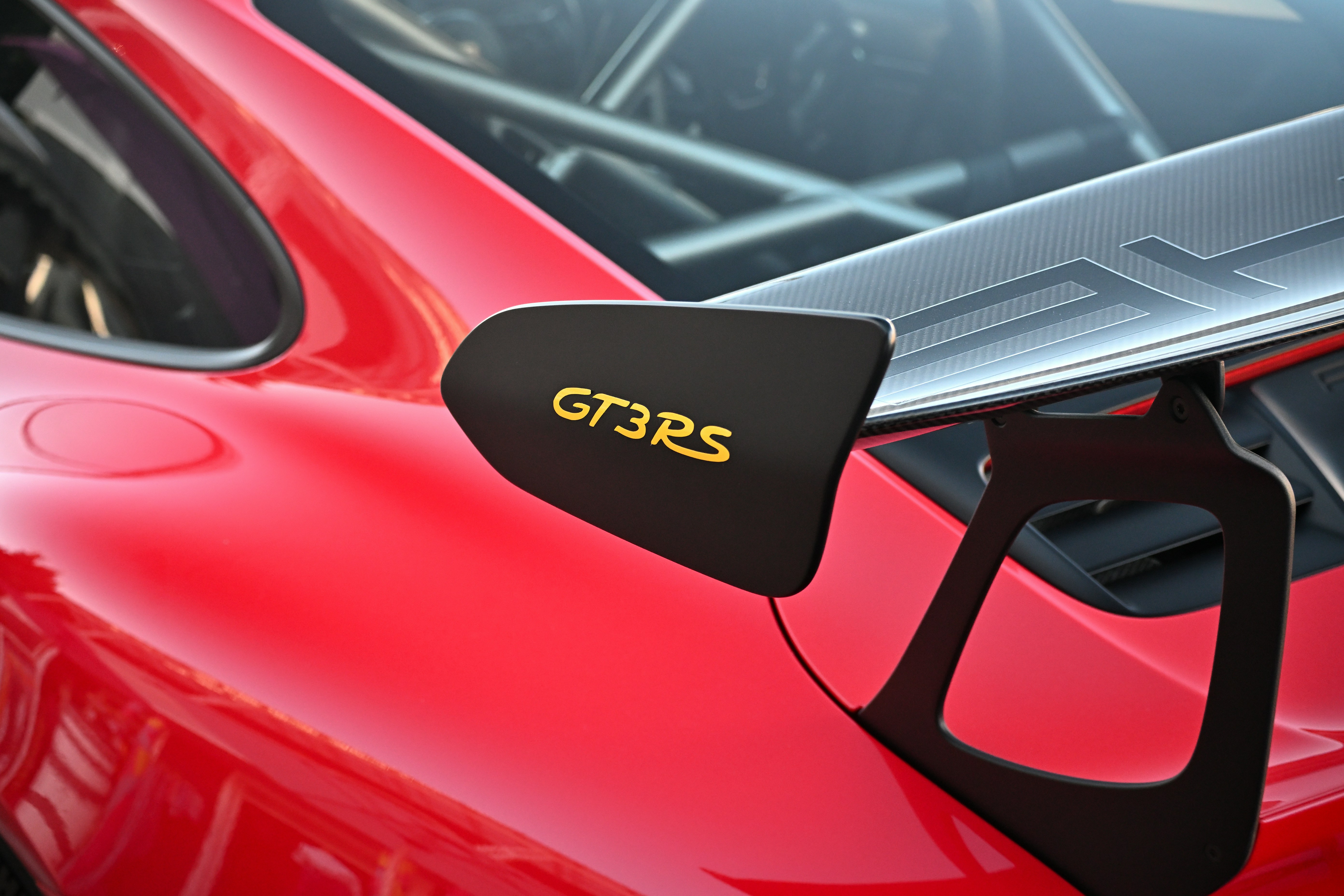 Red satin curves and a high-set wing: close-up of a GT3RS wing and rear deck