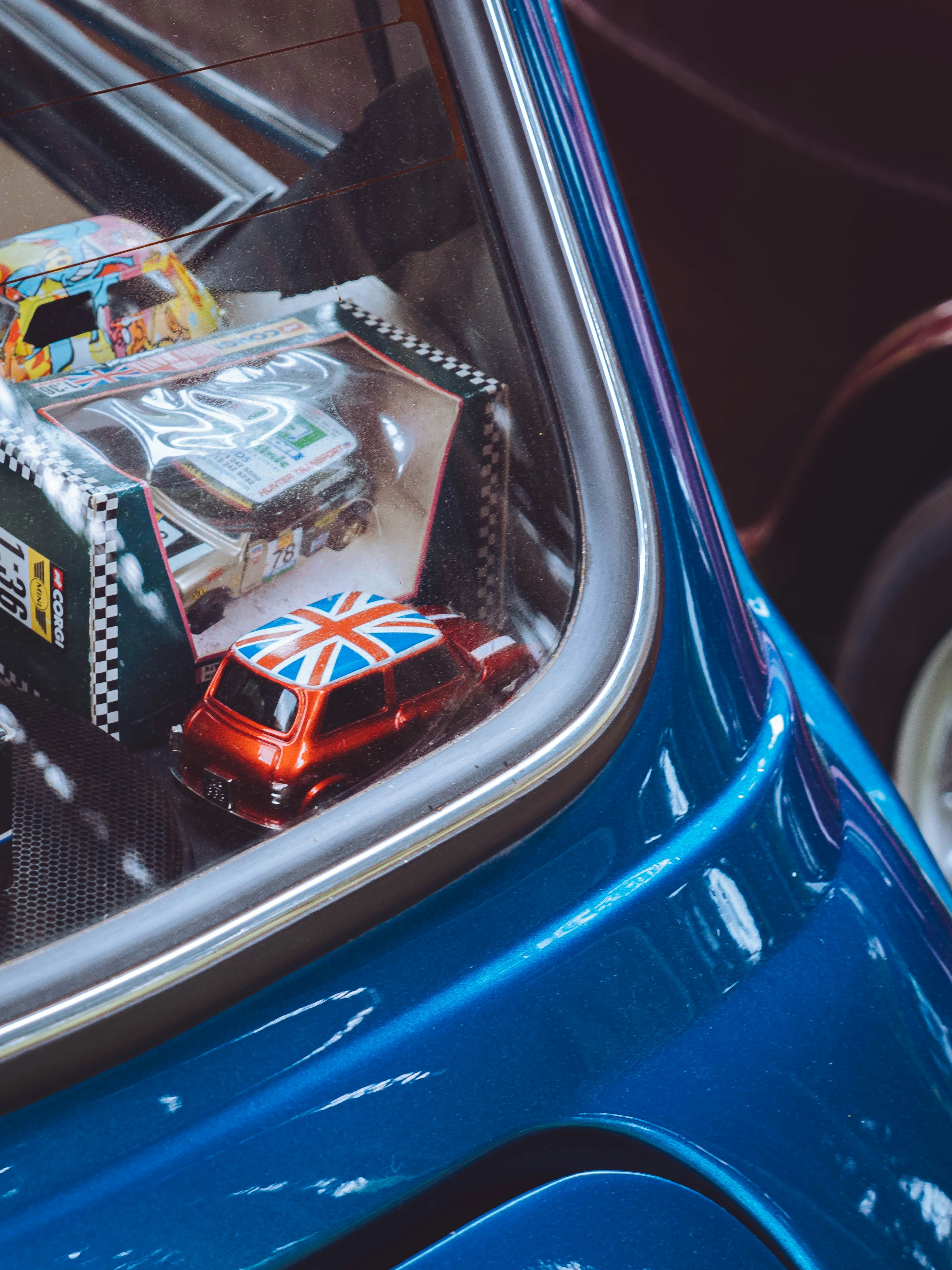 Miniature British Flag Car tucked in the rear window of a blue vintage car