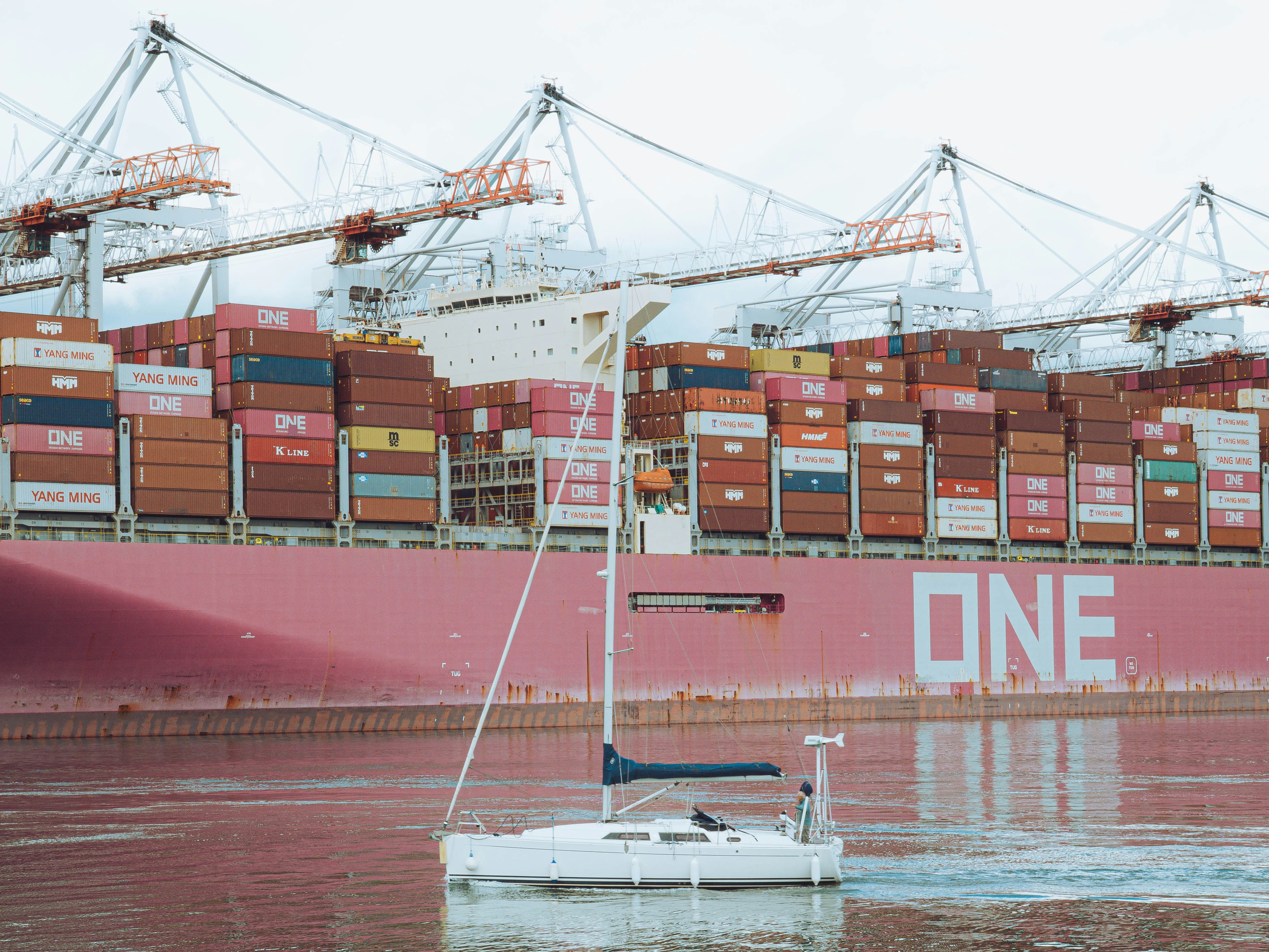 Tiny Sailor, Giant Horizon: A White Boat Amidst A Sea of Shipping