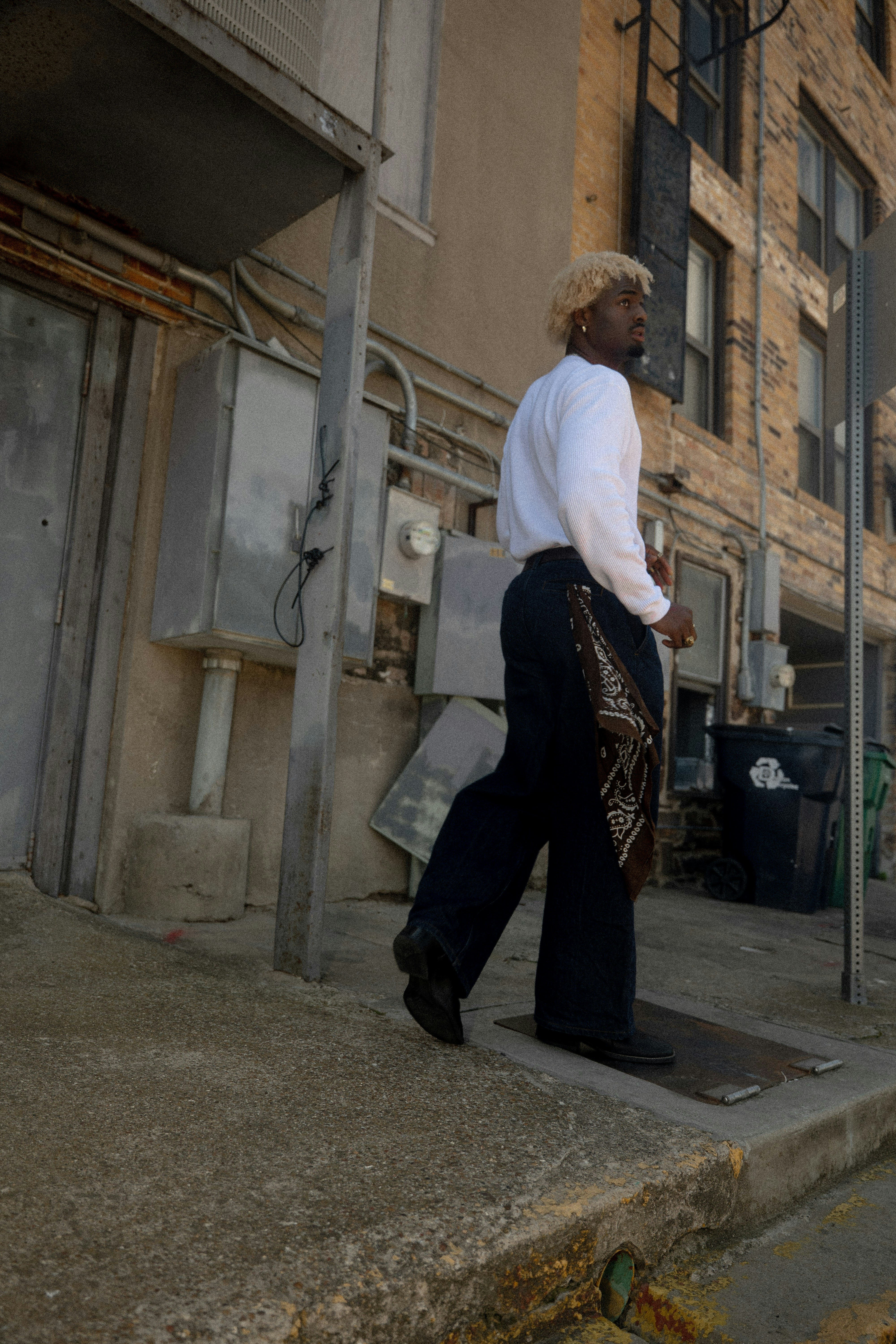 Urban Pose: Man in White Shirt Strides past Industrial Backdrop