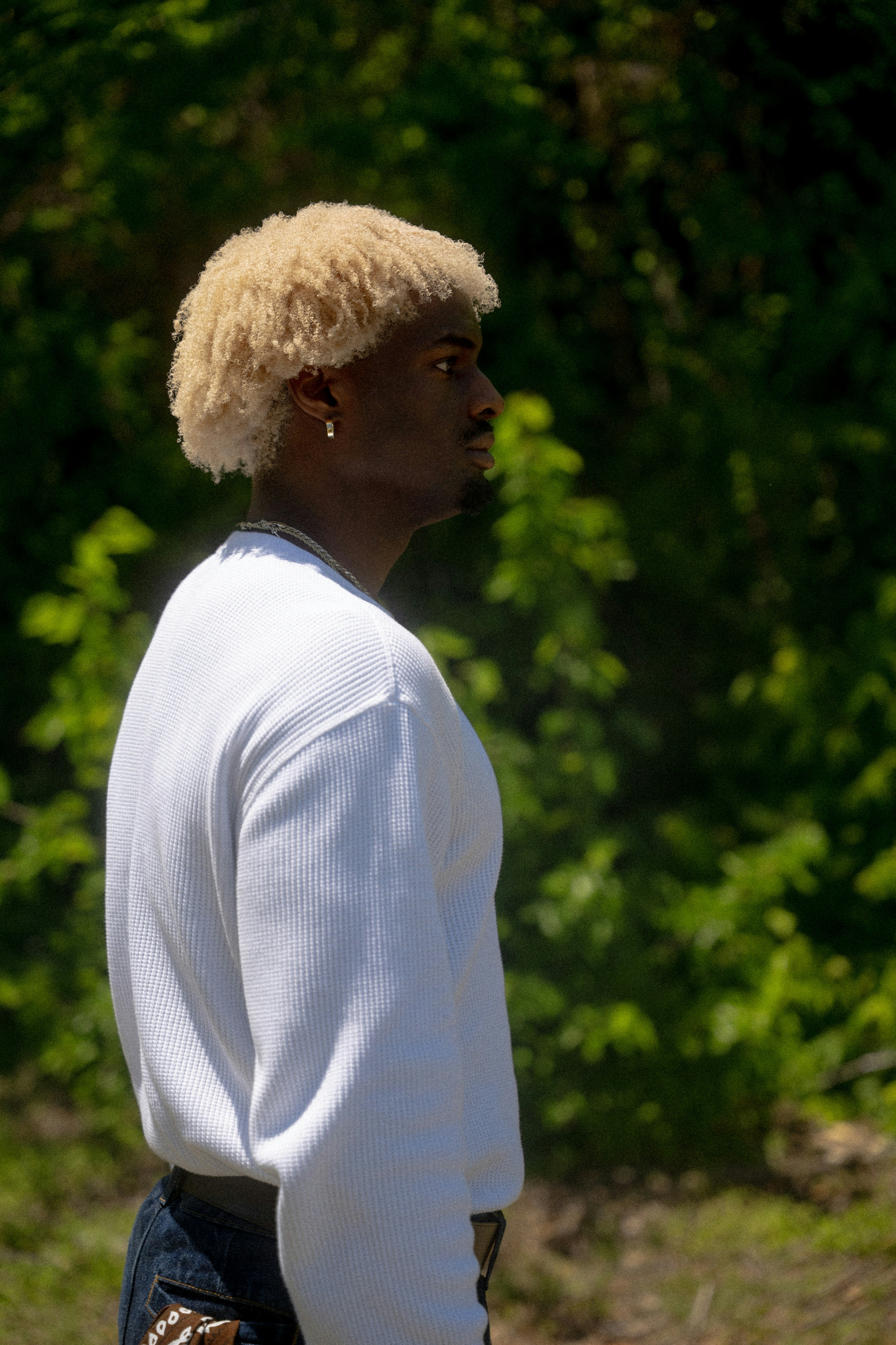 Profile in the Sun: A Man with Blonde Curls in a Quiet Clearing
