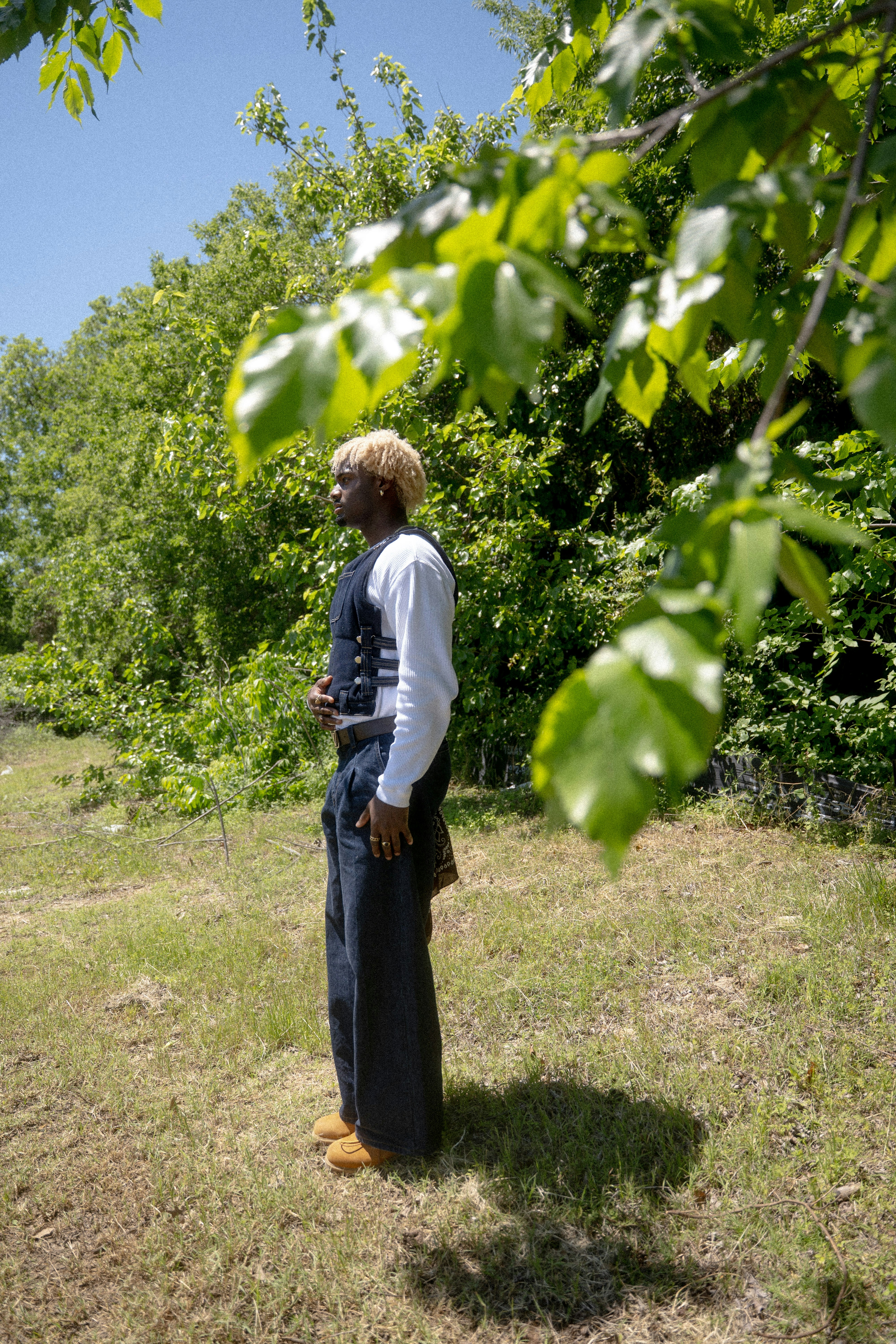 Standing in the Orchard: A Man in Denim and White in Sunlit Green
