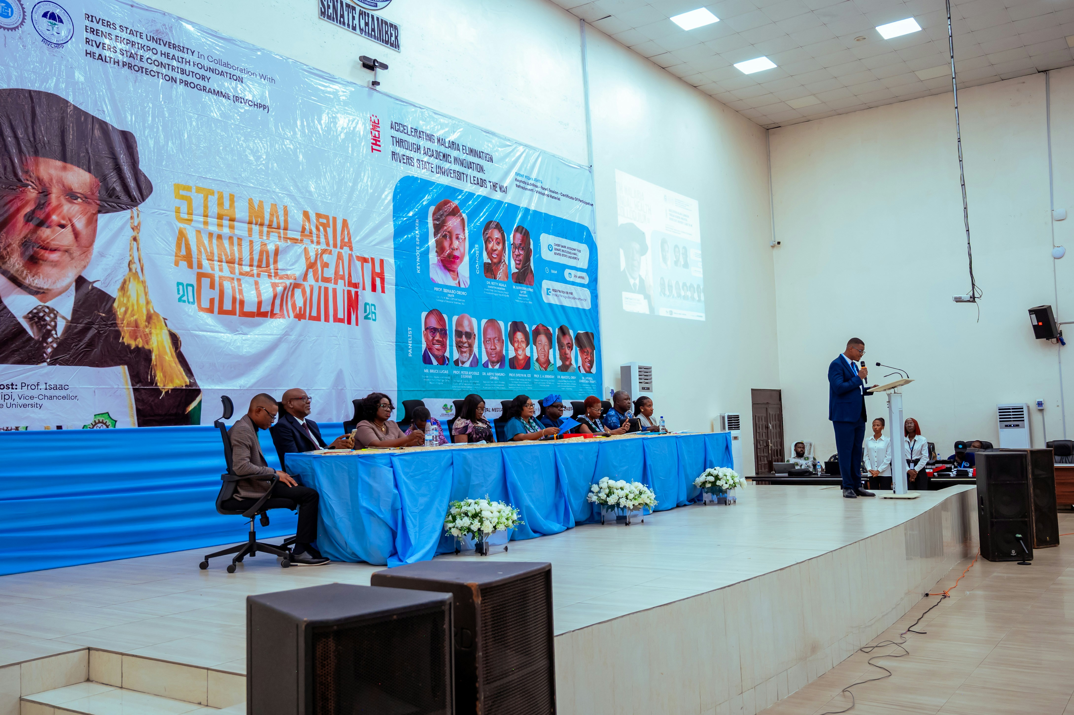 Panel at the Malaria and Health Conference: Speakers seated in front of a blue banner