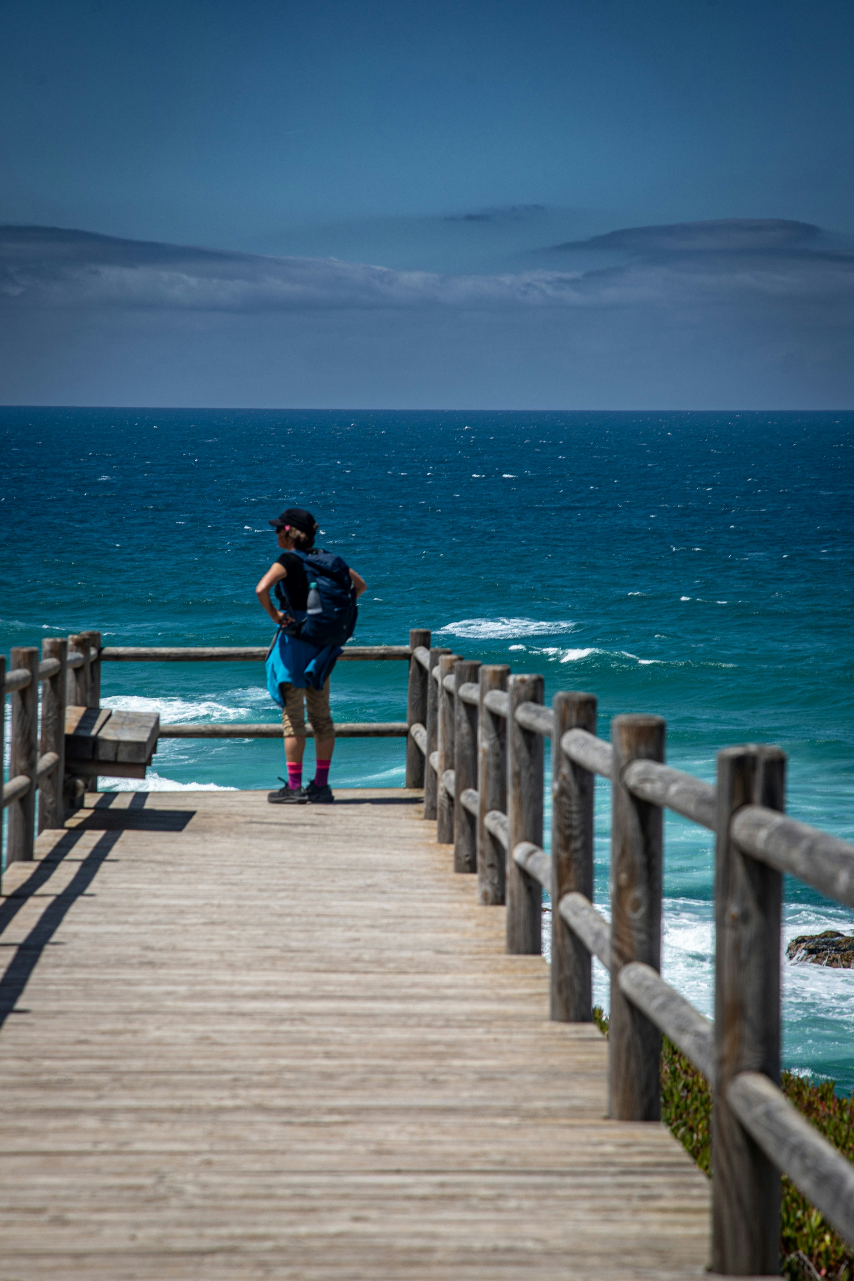 Path to the Horizon: A Hiker Stares Toward the Sea from a Wooden Pier