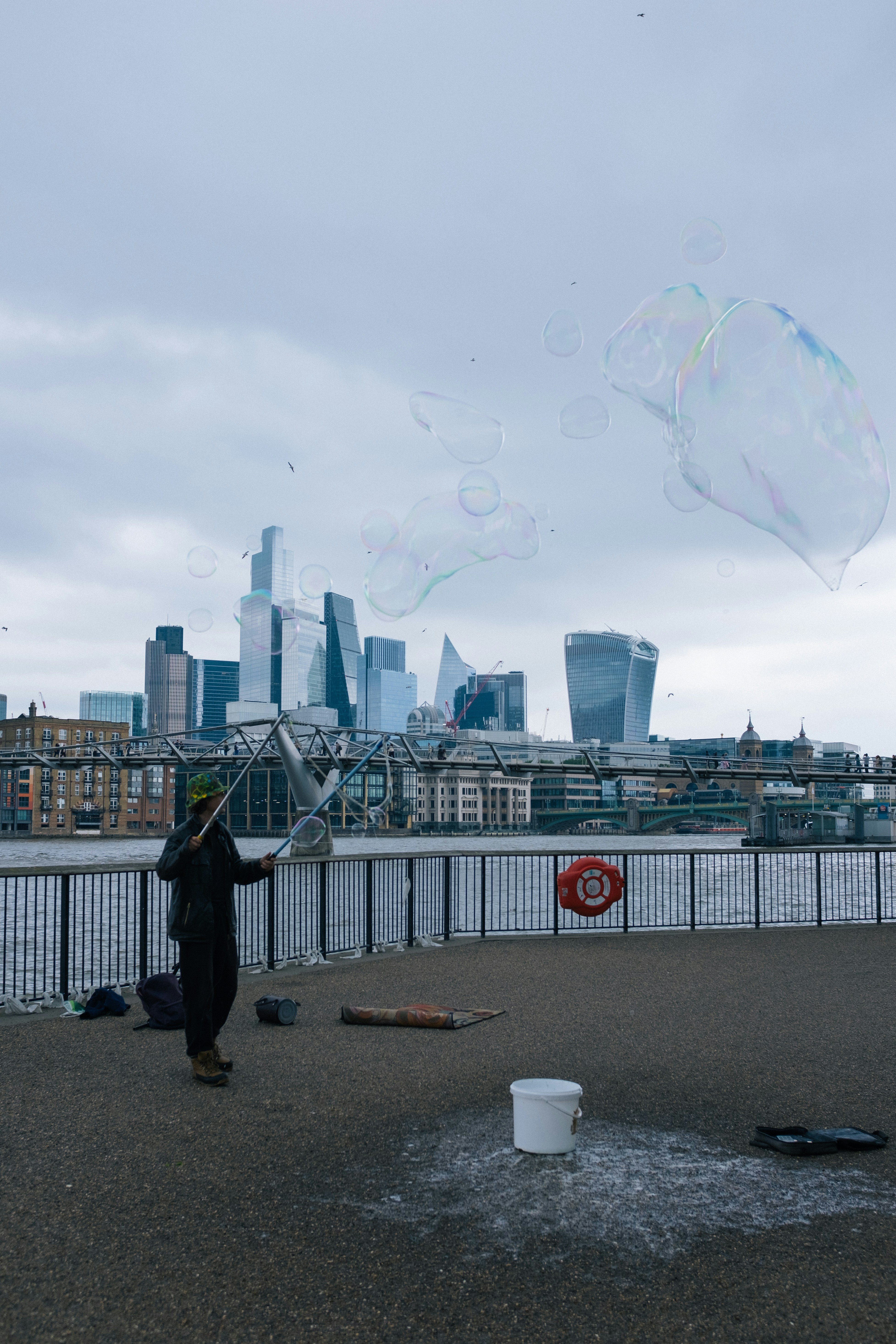 Bubble Artisan on the Thames: A Street Performer Aiming for Skyward Spheres